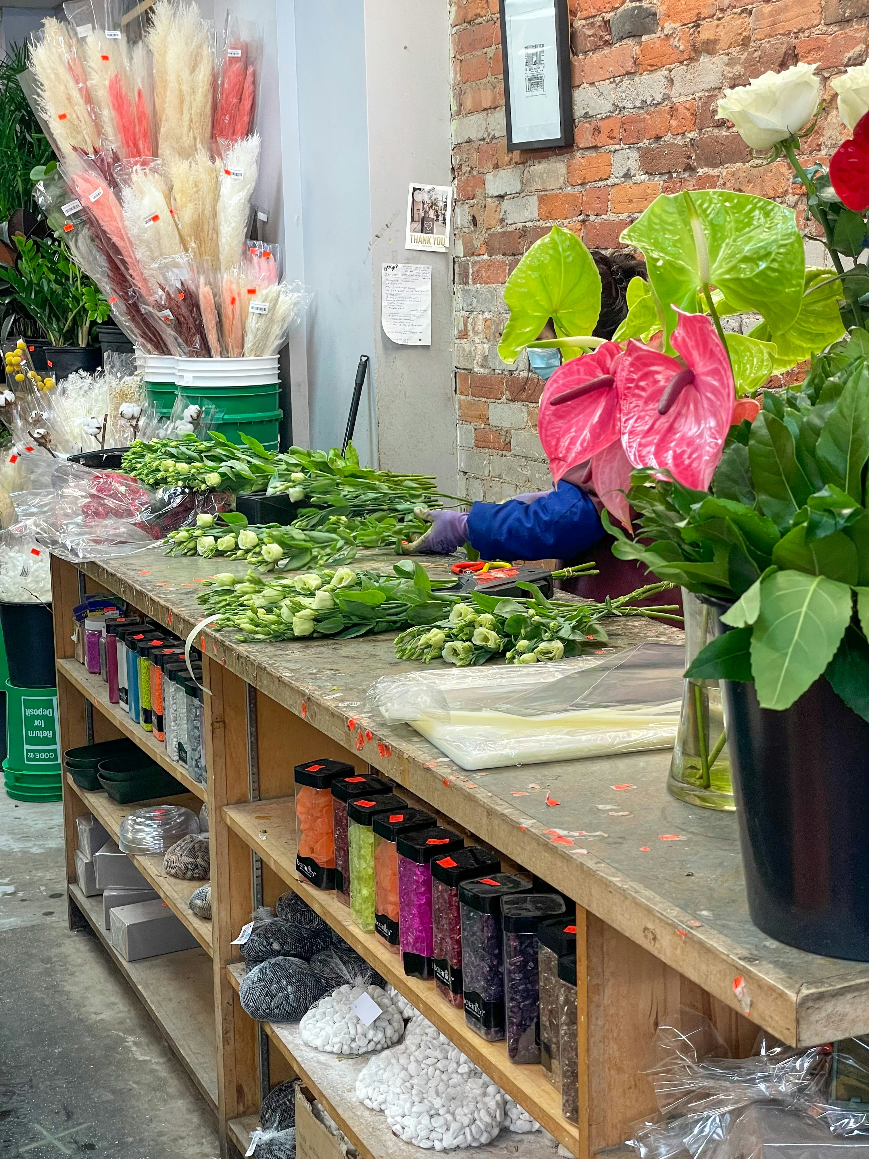 Florist’s Workbench: Fresh Greens and Potted Blooms in a Brick-Backed Shop