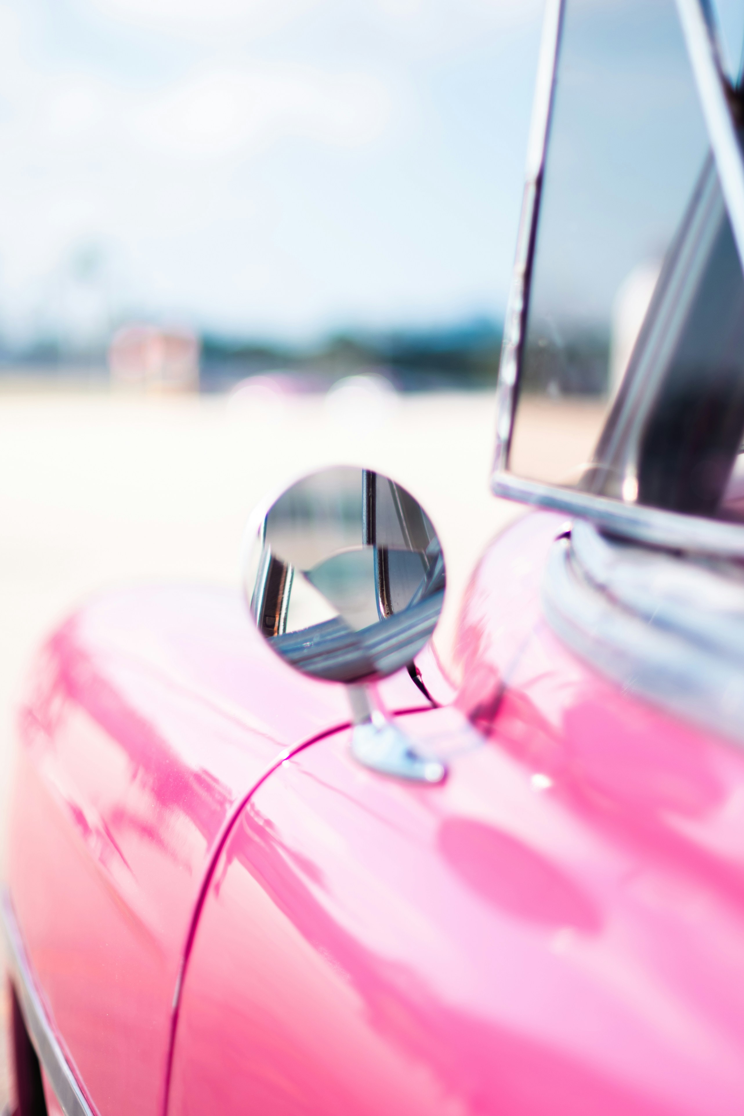 Chrome Mirror, Pink Classic: A Close-Up of a Vintage Car’s Side View