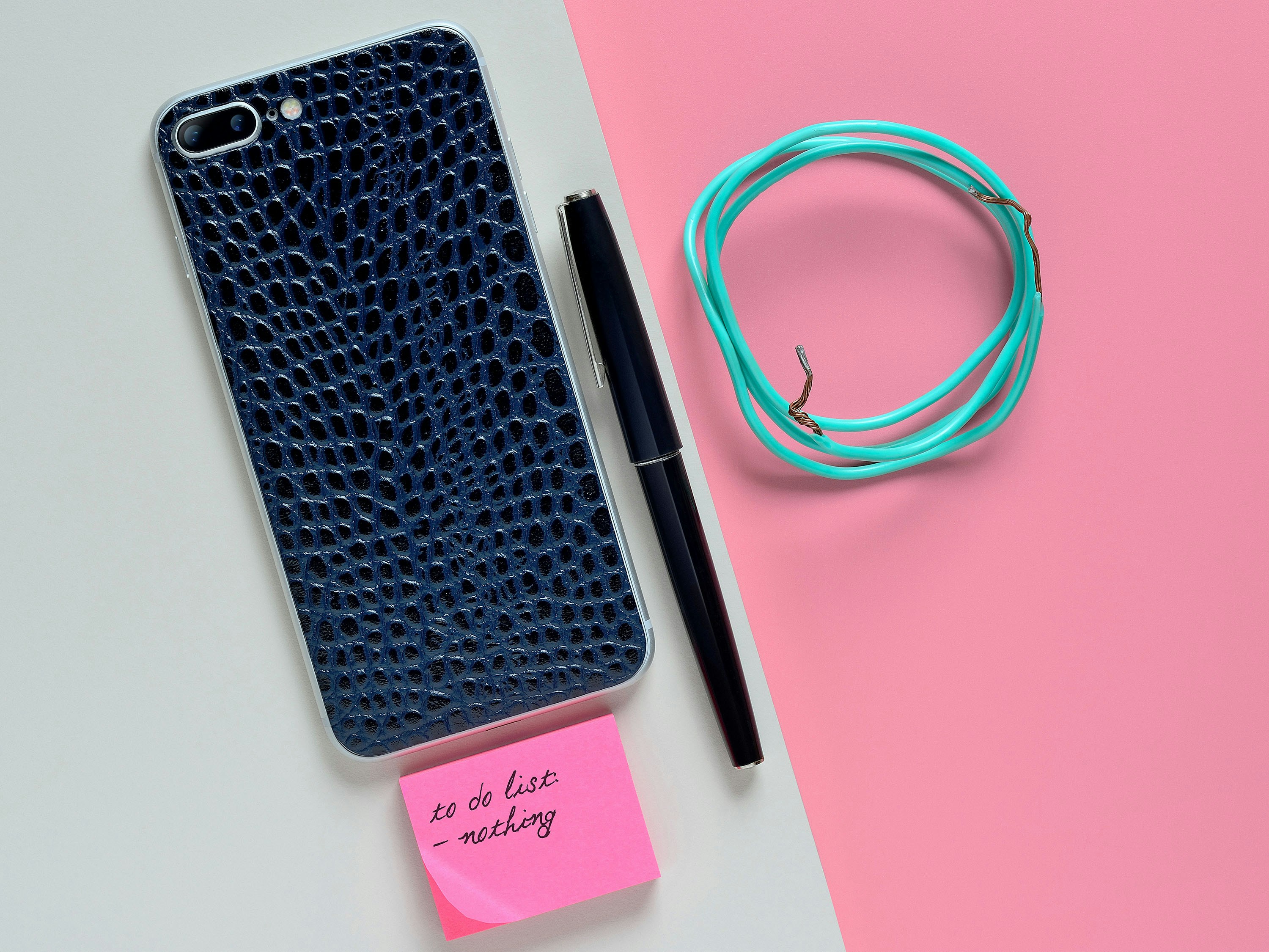 Navy textured phone case with mint cable and pink sticky note backdrop