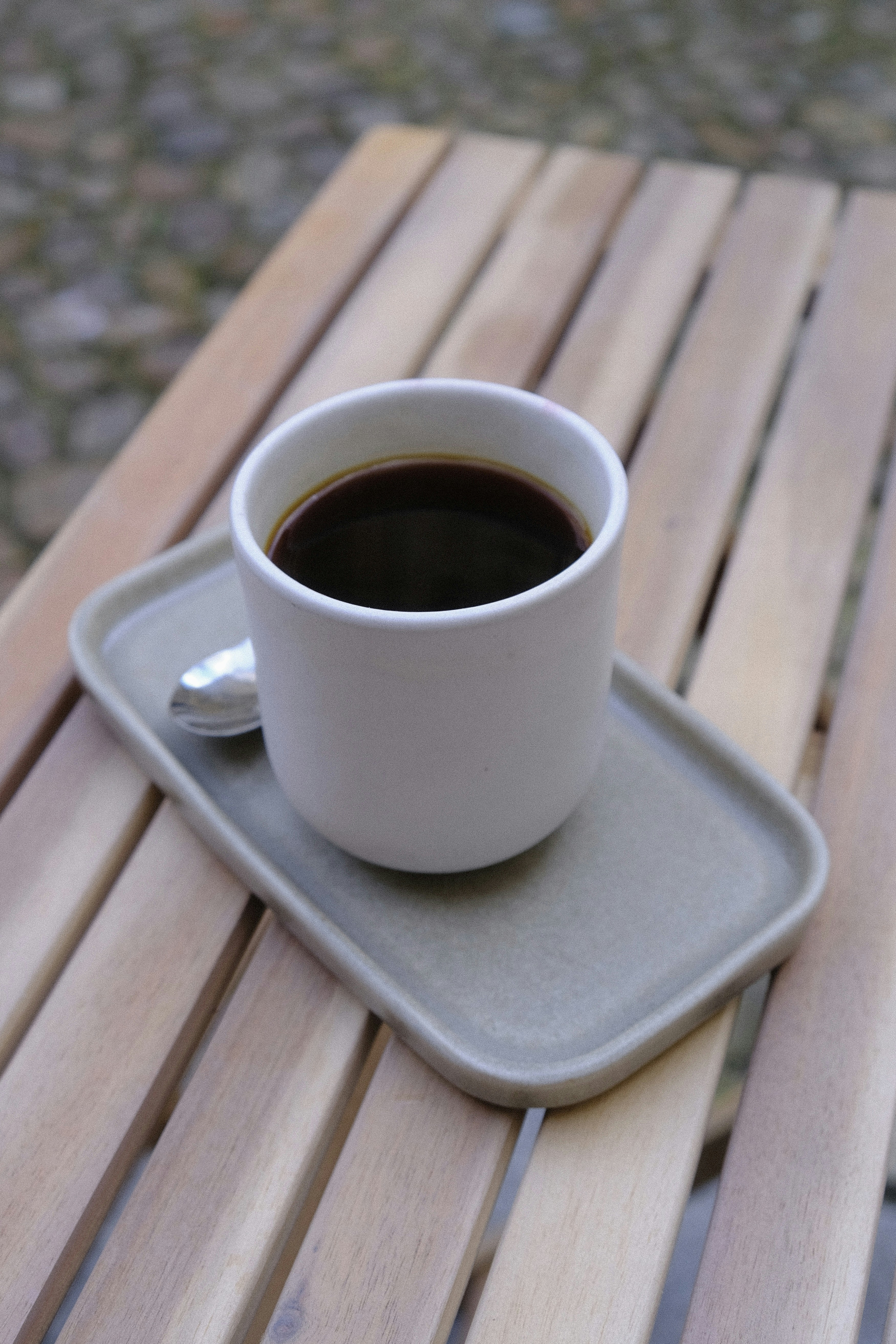 Morning Minimalism: Ceramic Cup of Black Coffee on a Slatted Outdoor Table