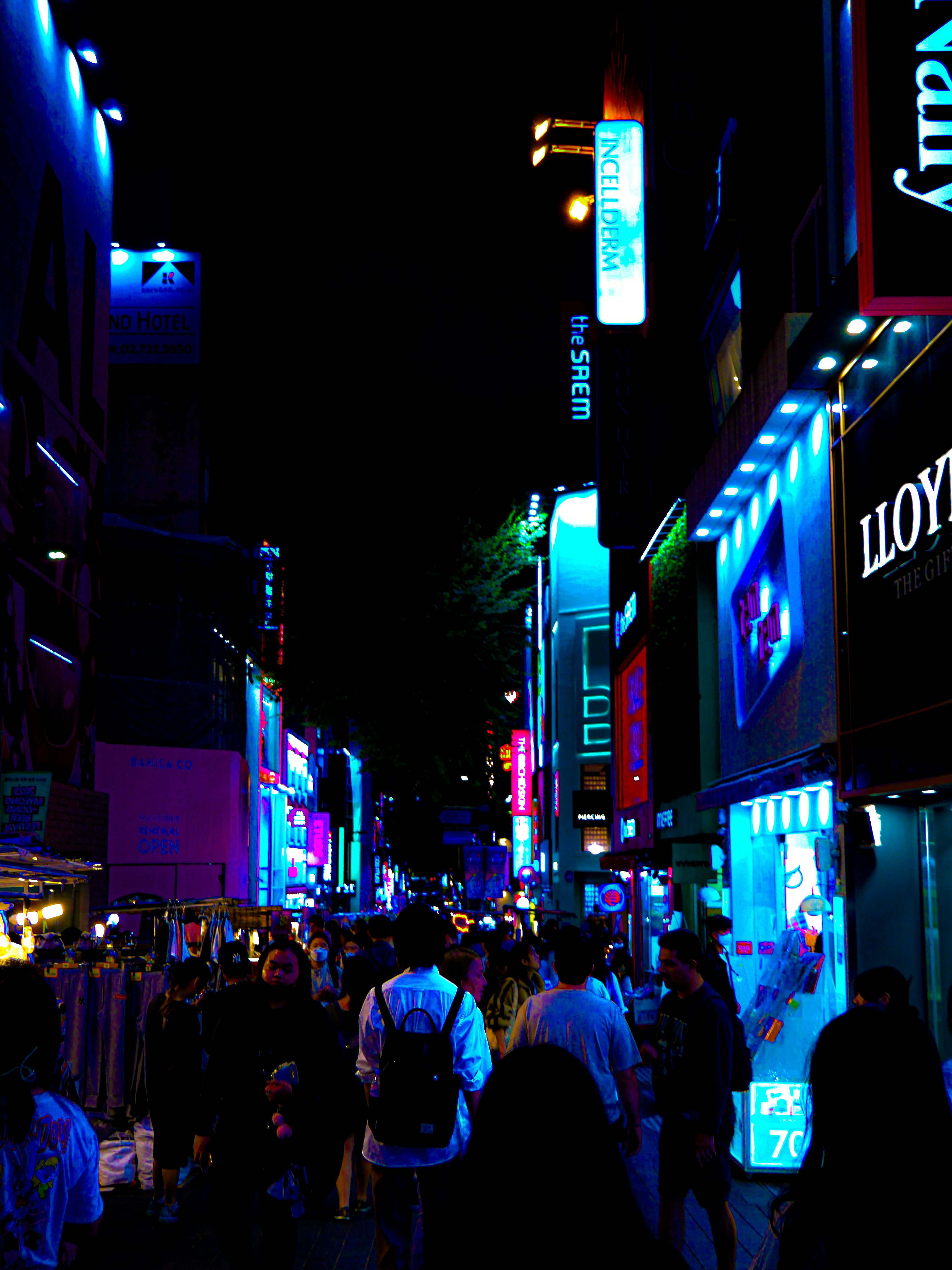 Midnight Neon Corridor: Crowds Under Blue Downtown Signage