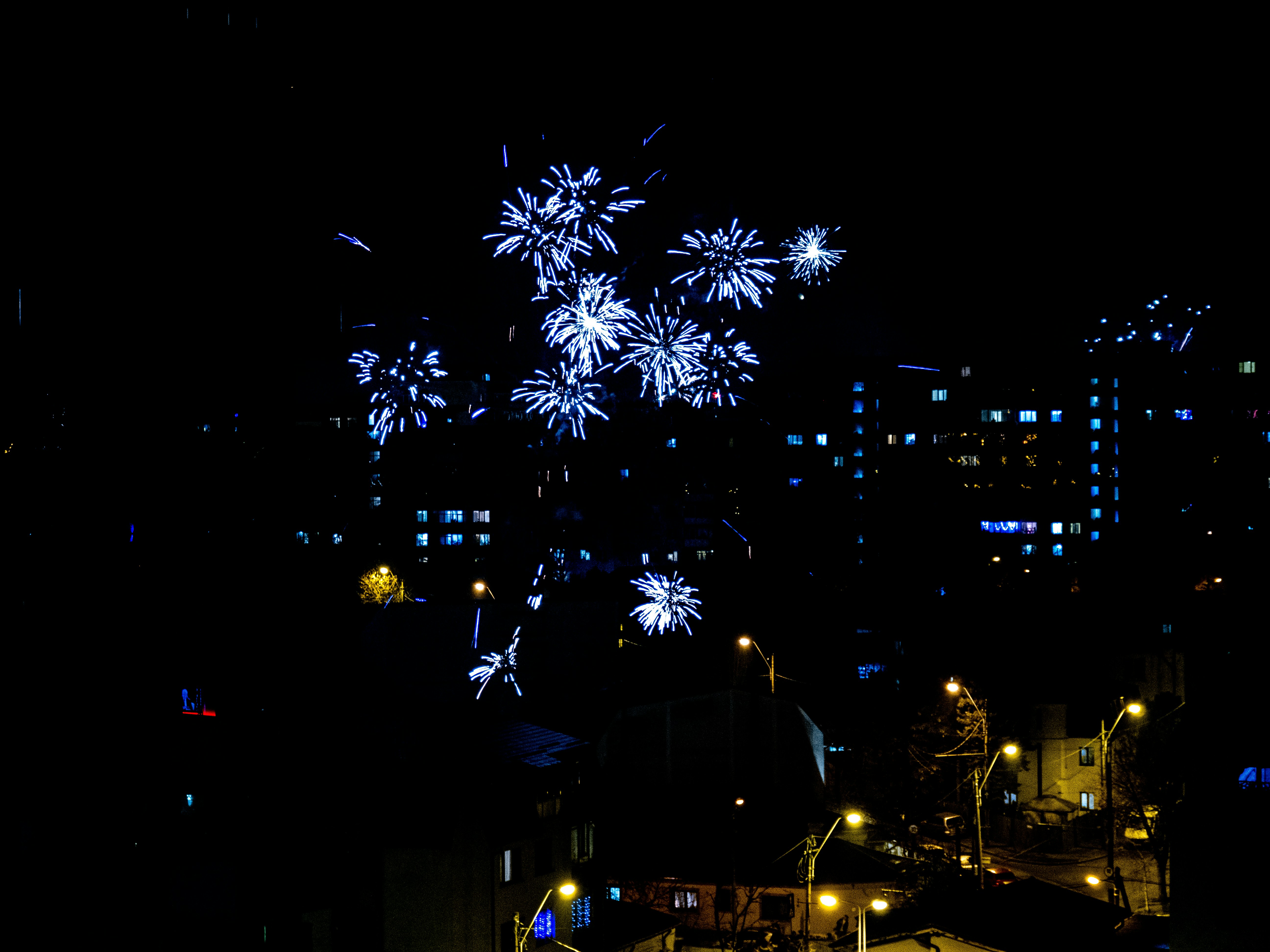 Urban Nocturne: Fireworks Dance Over City Lights