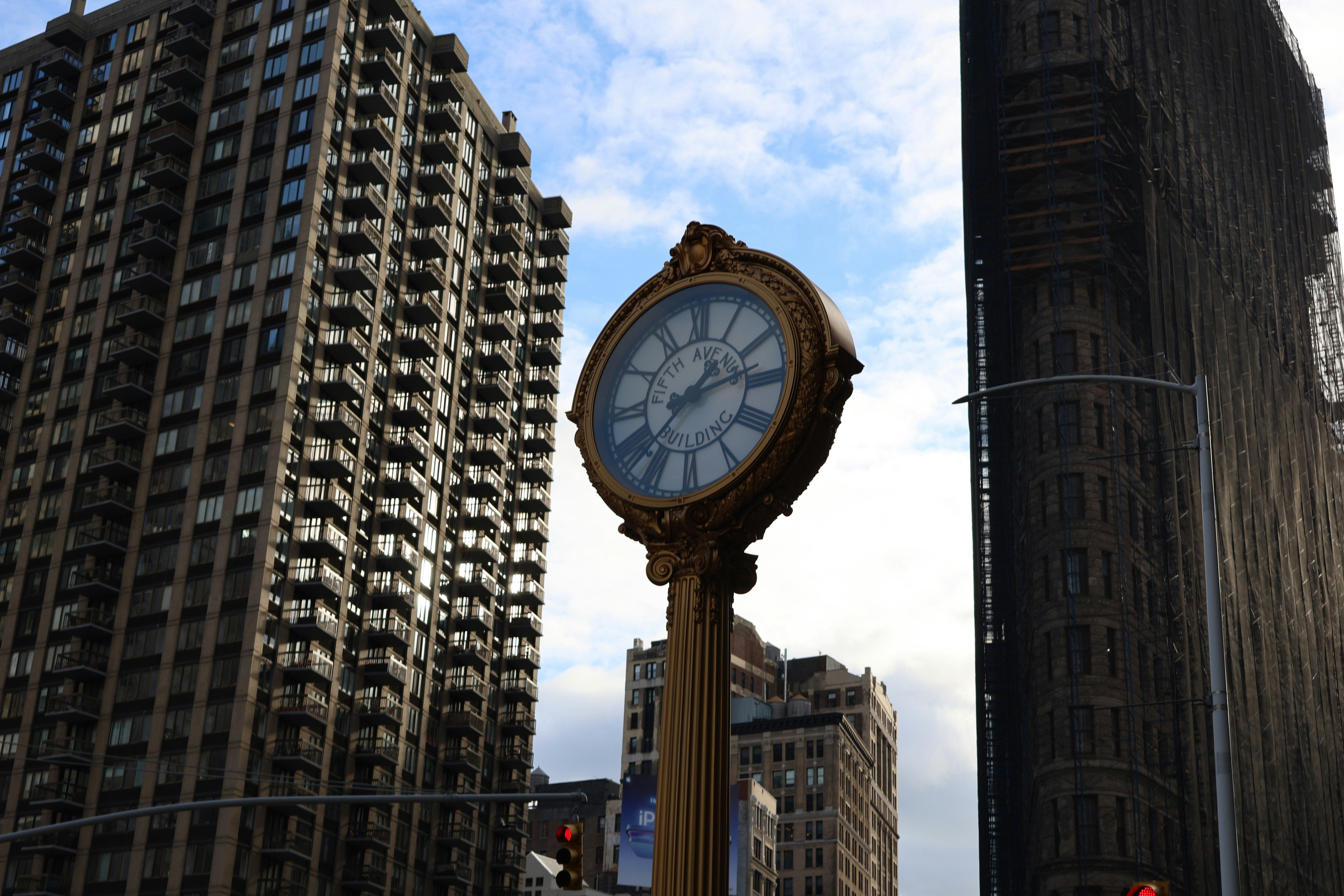 Vintage street clock against towering urban skyscrapers and a blue sky.