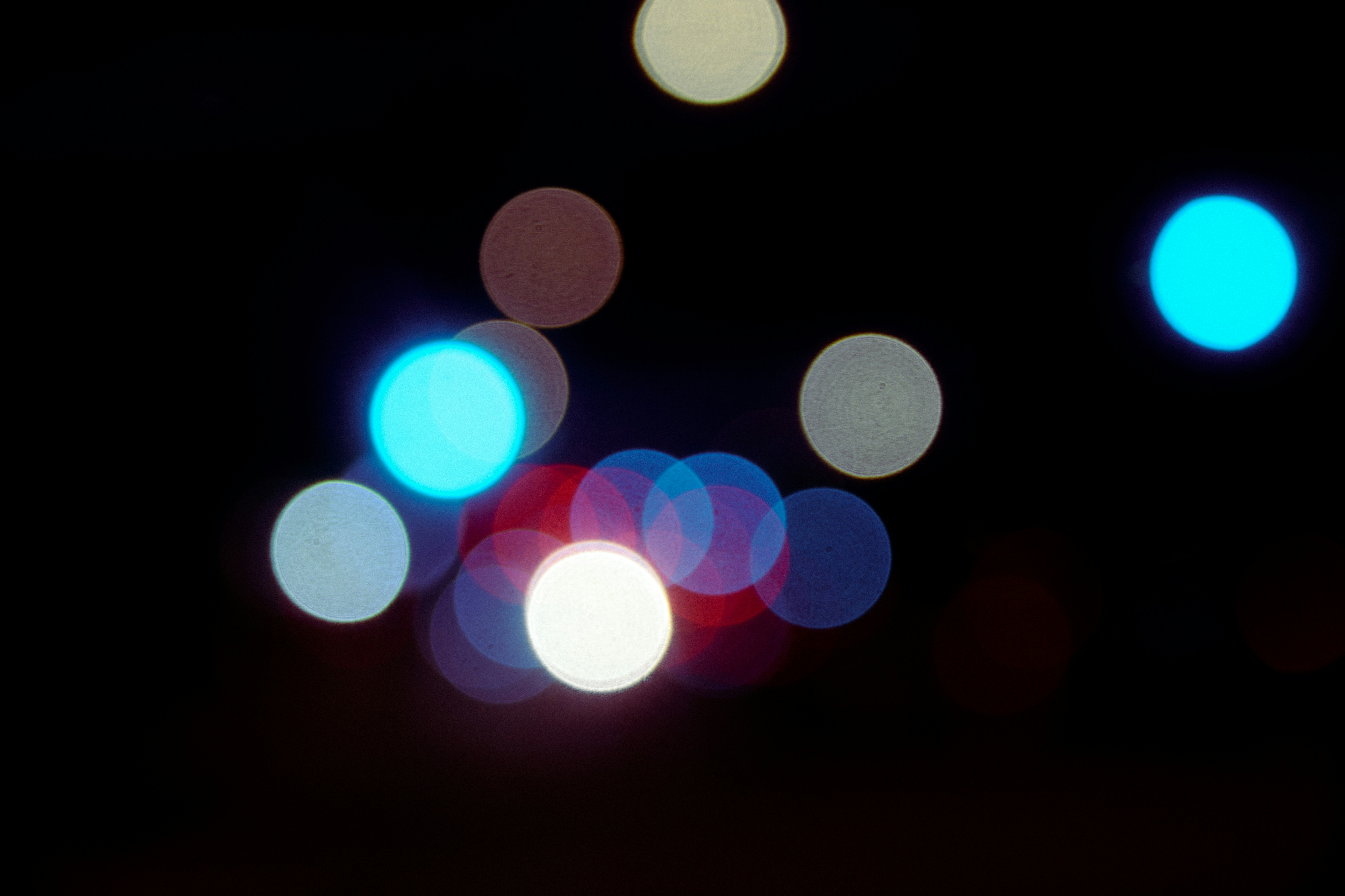 Colorful bokeh circles in vibrant blues, reds, and whites against a dark backdrop.