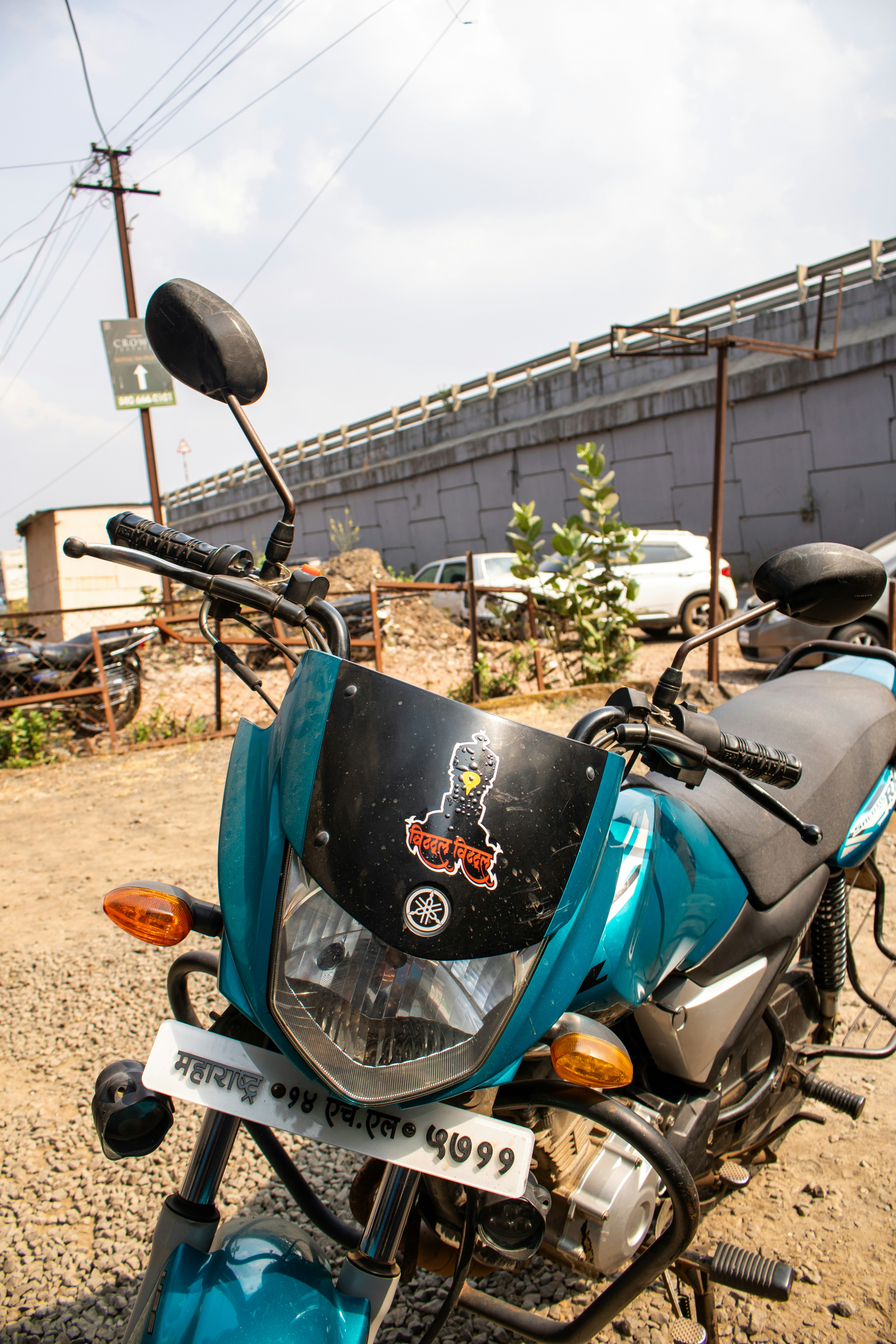 Stickered Turquoise Front: A Sunlit Parked Motorbike