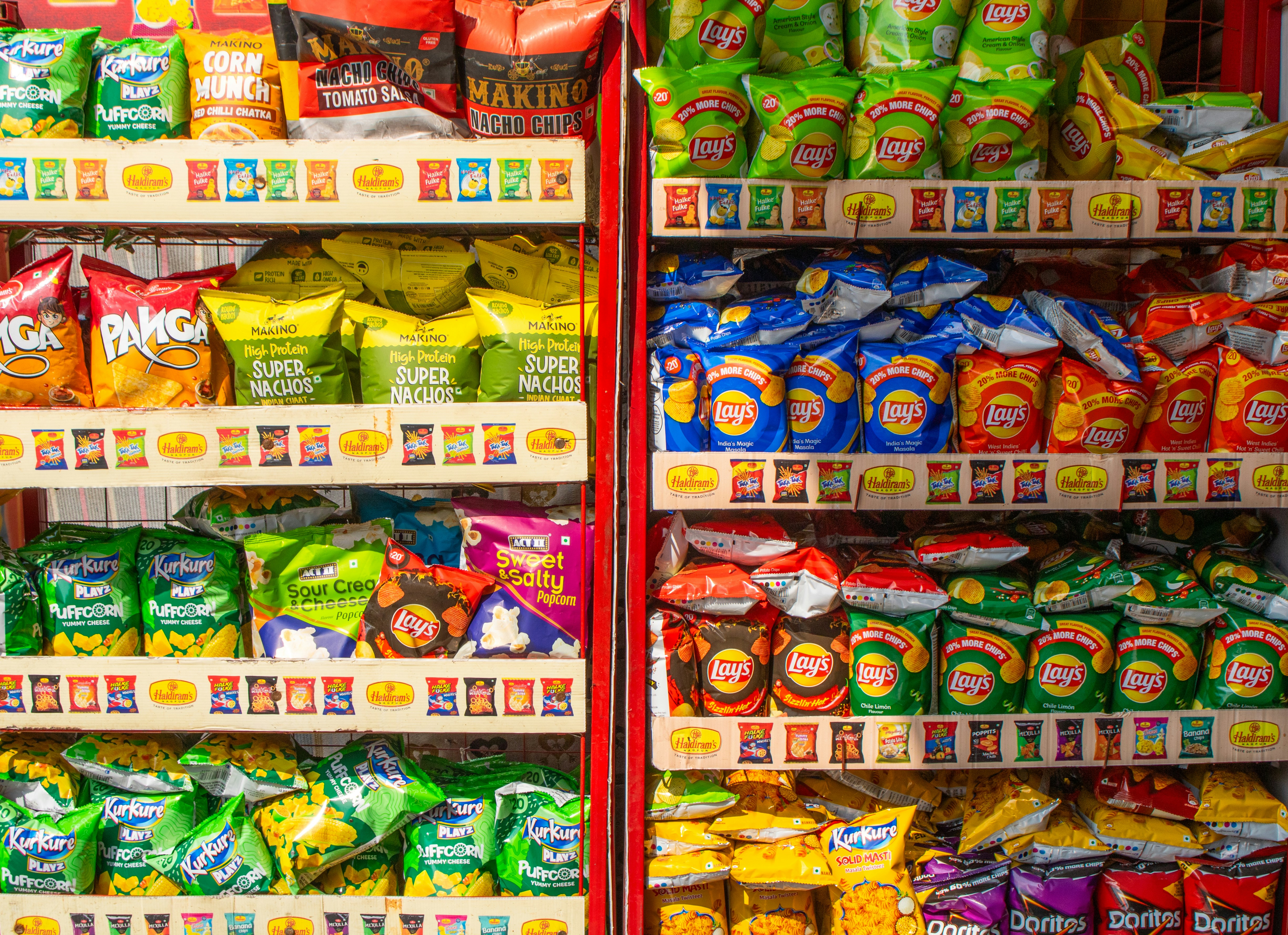 Brightly colored chip bags line shelves, creating a vivid pattern of reds, greens, yellows, and blues under warm lighting.