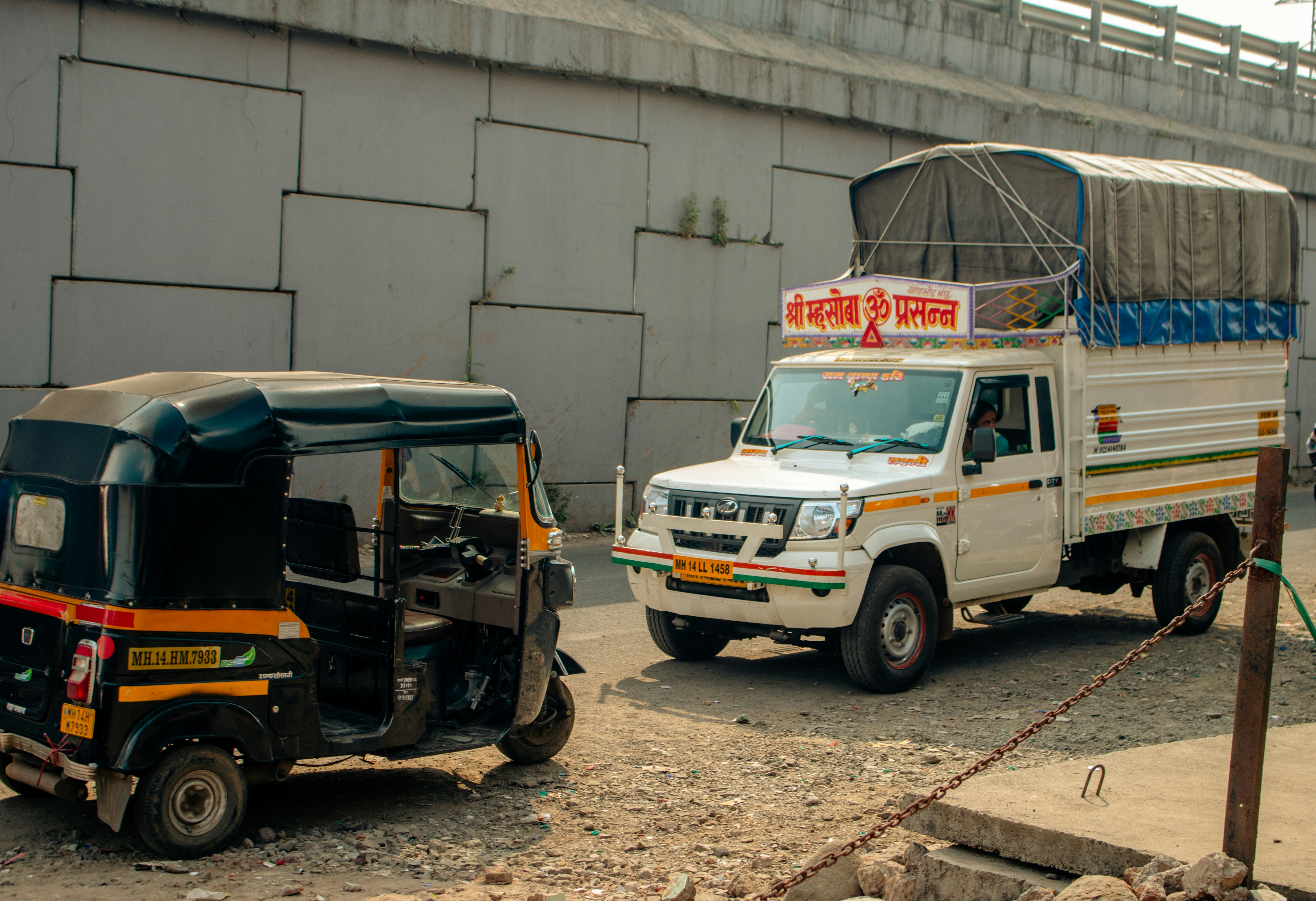 Standoff at the Barricade: White Cargo Truck and Auto Rickshaw by a Concrete Wall