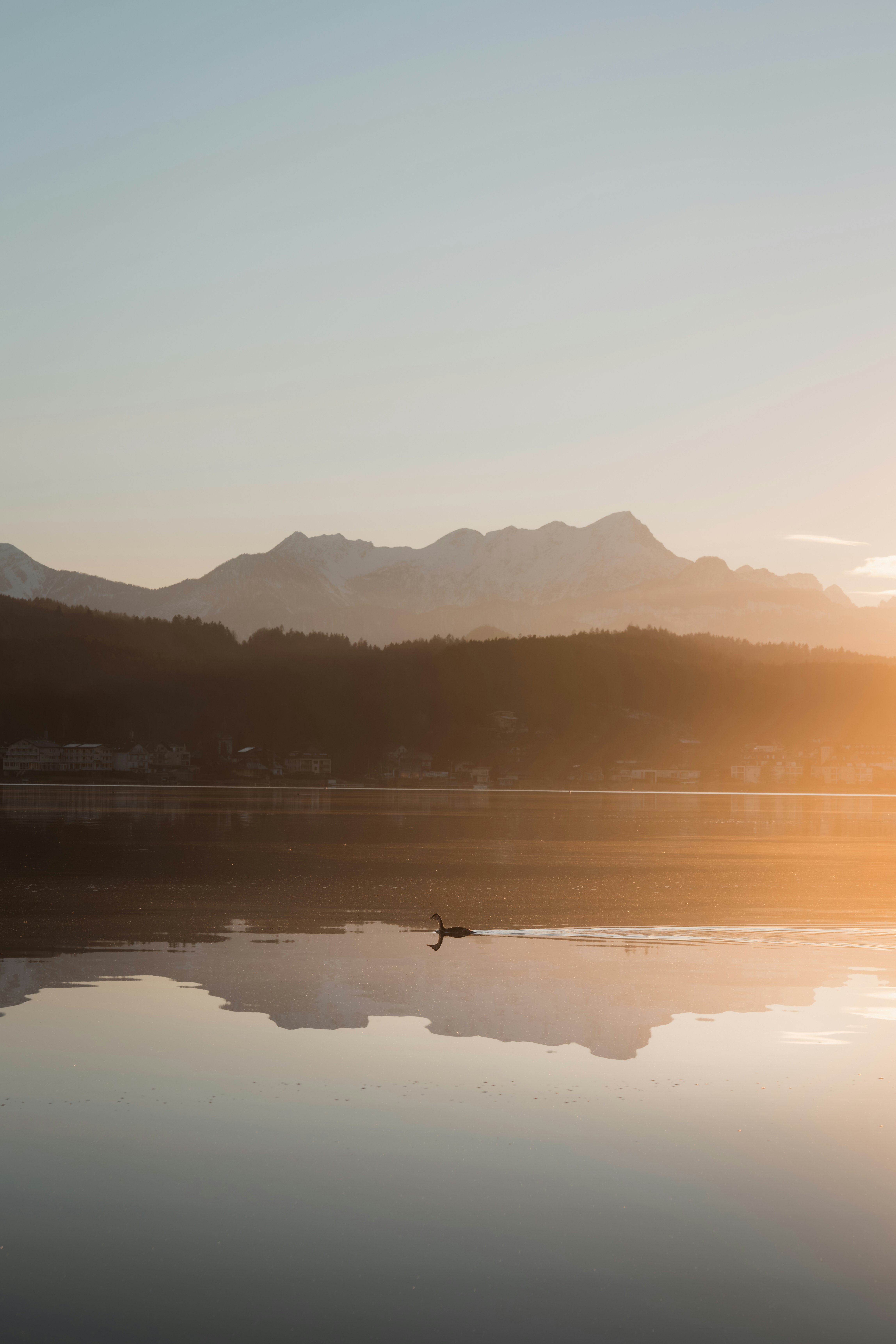 The sun is setting over a lake with mountains in the background photo ...