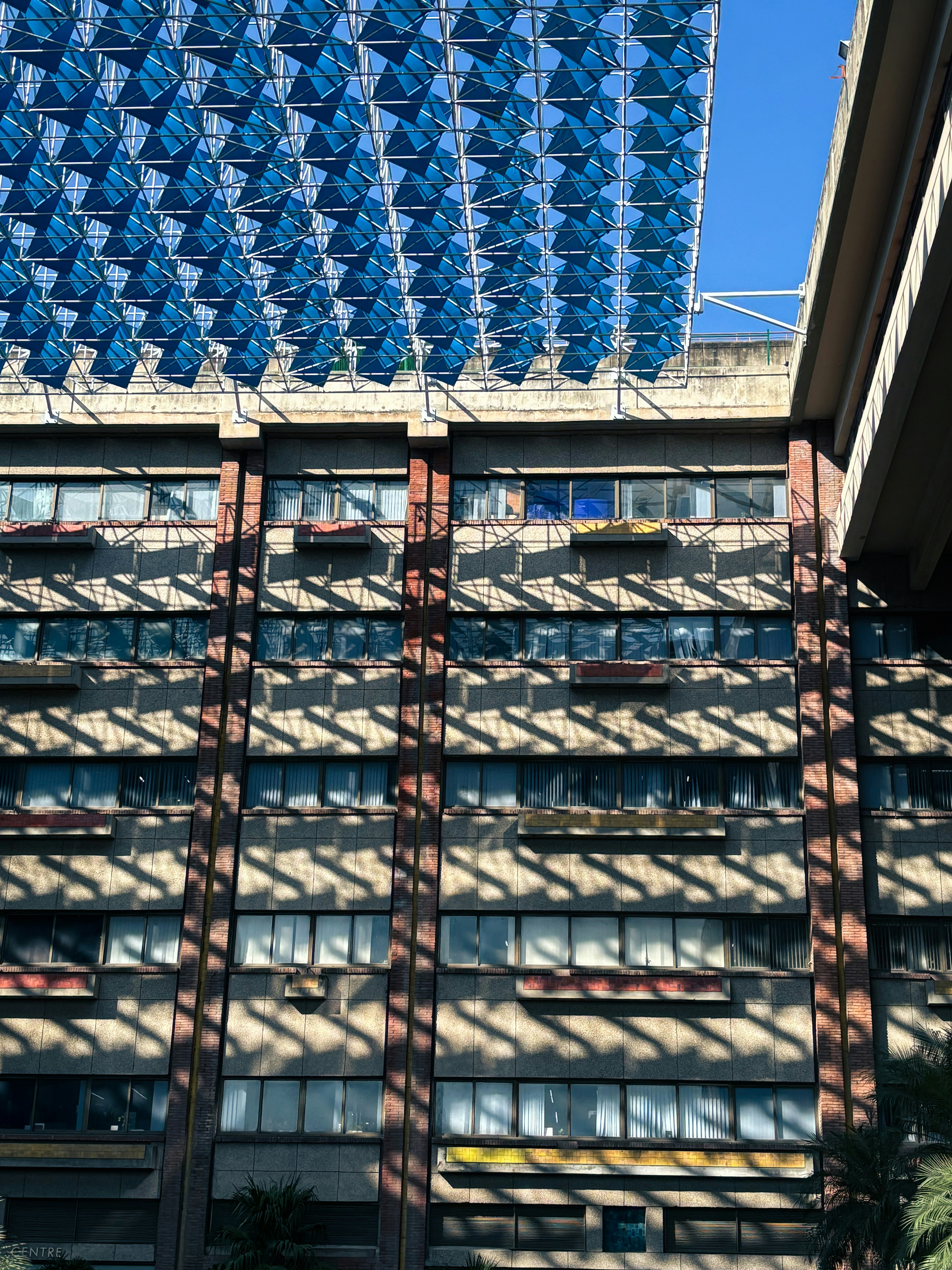Blue Geometric Canopy Over Brick Facade: Shadow-Patterned Urban Architecture