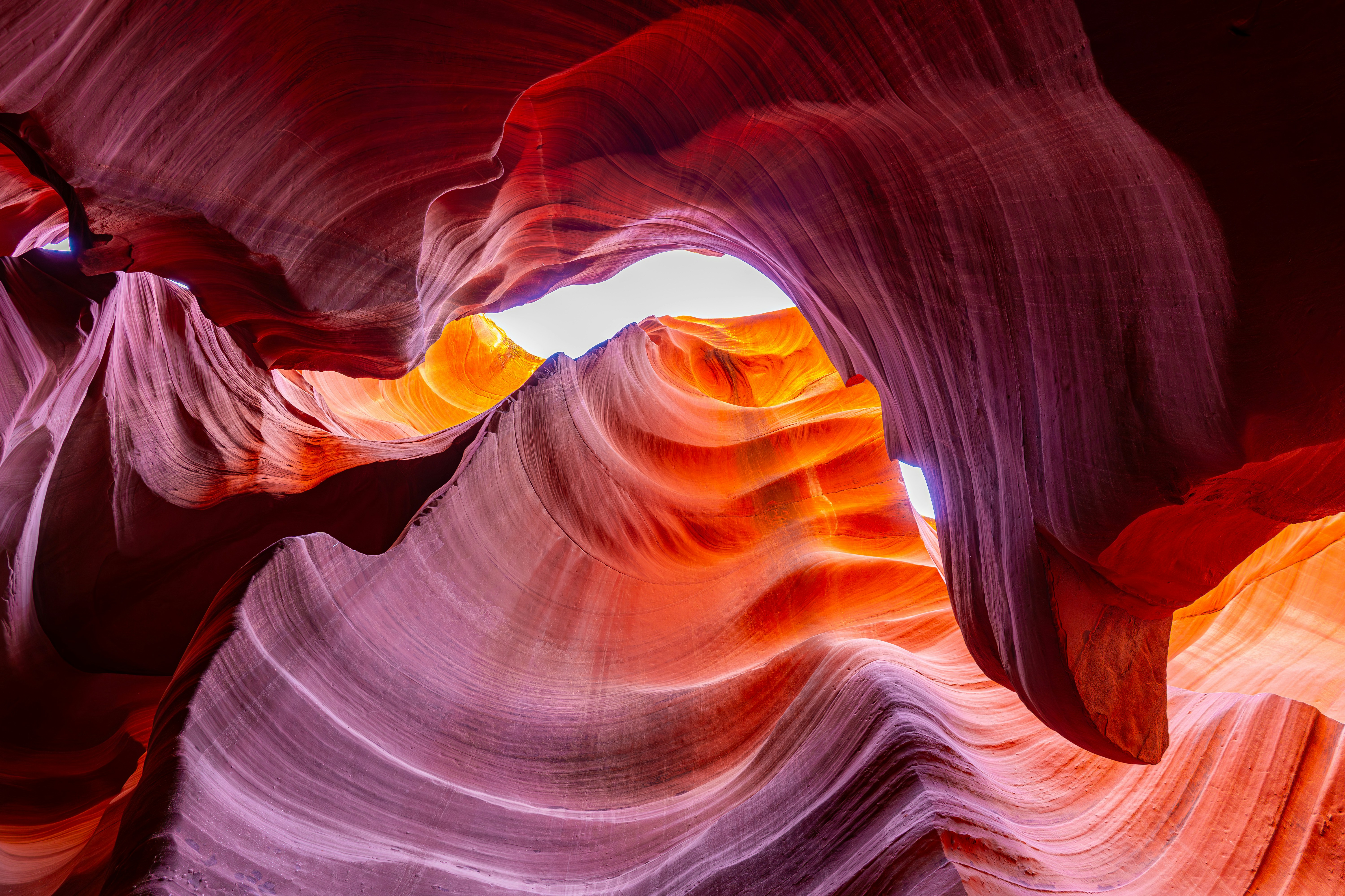 Curving sandstone formations in Antelope Canyon illuminated by warm sunlight filtering through narrow openings.