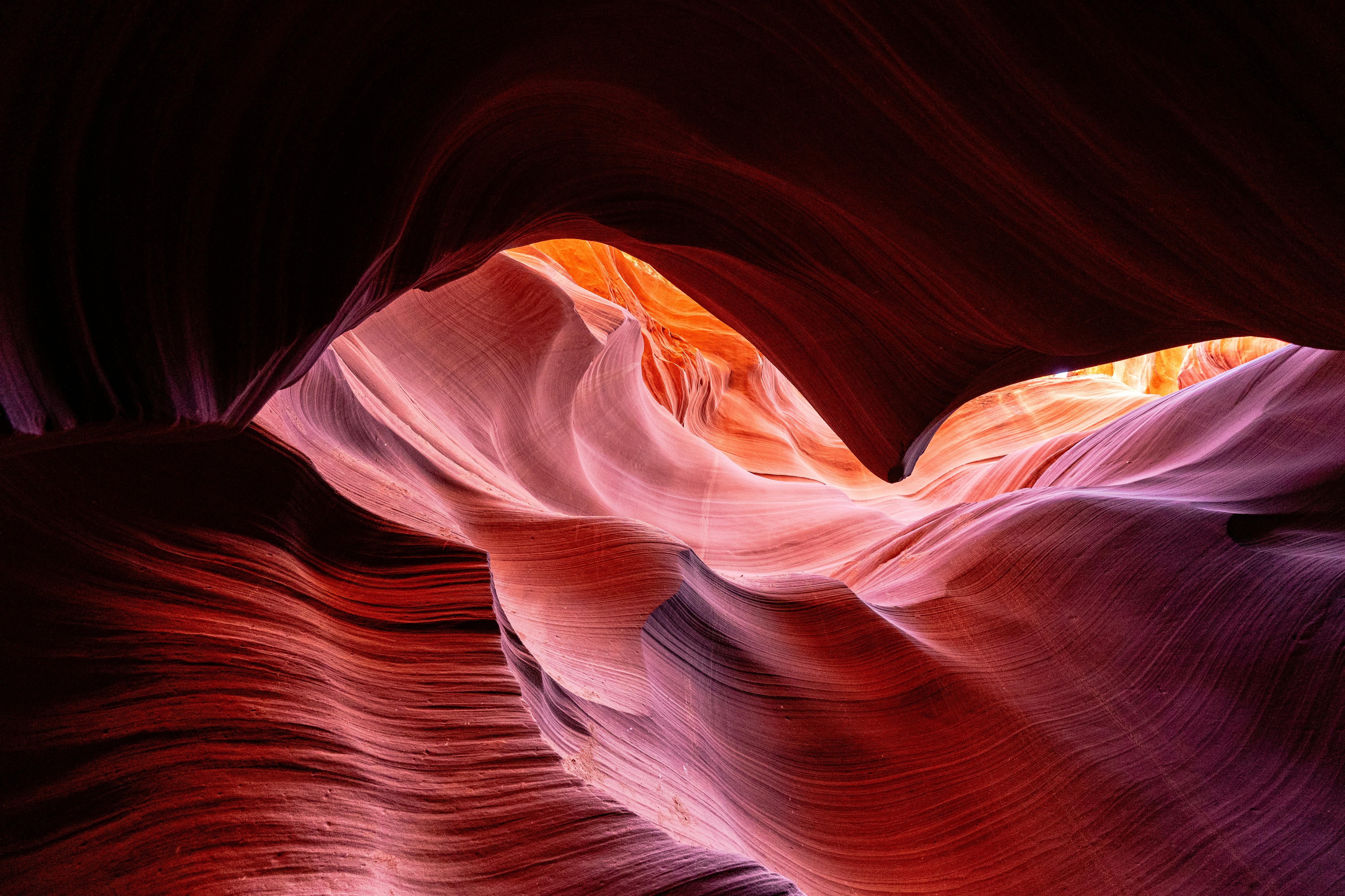 Flowing sandstone formations in Antelope Canyon illuminated by warm natural light filtering through narrow openings.