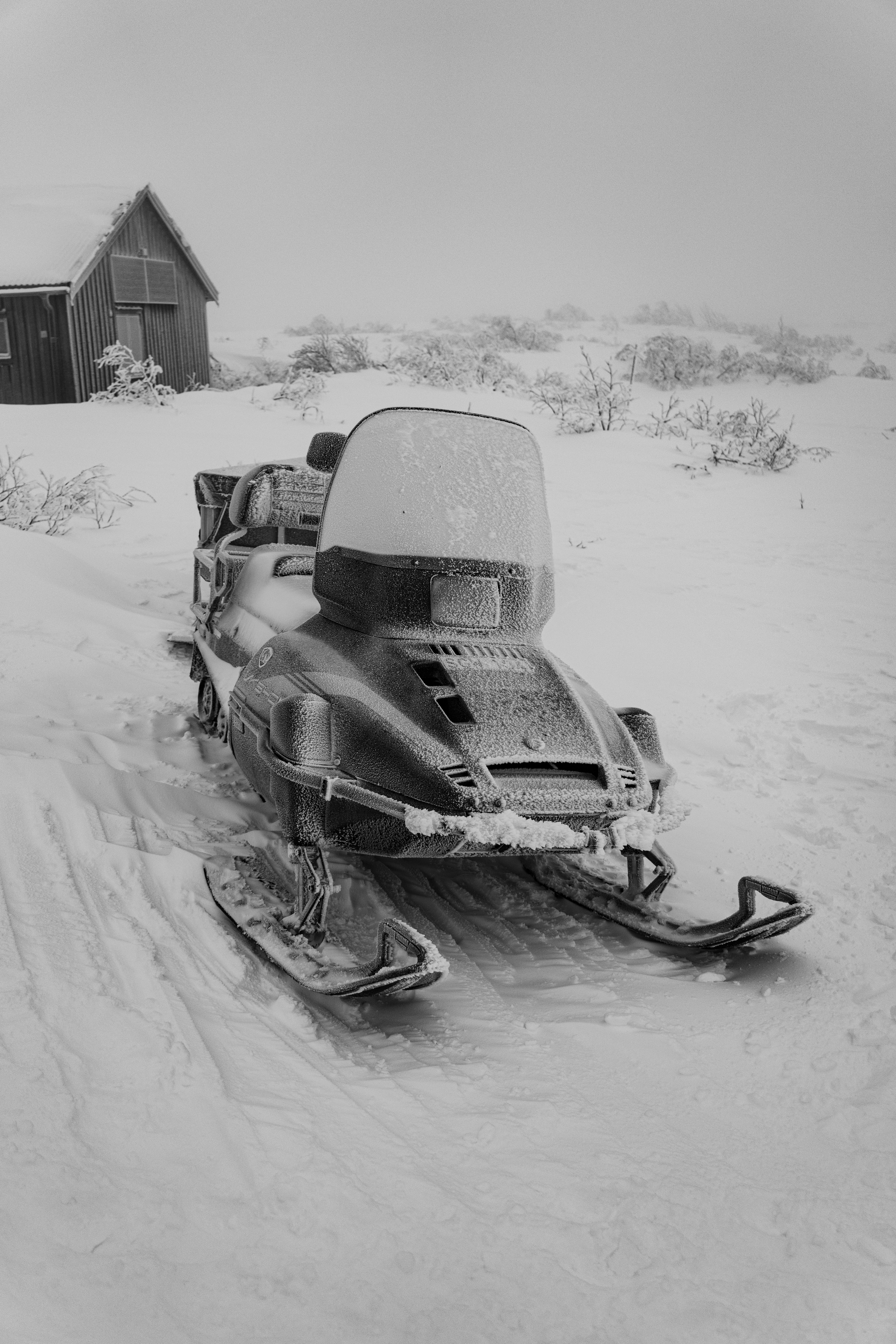 Icebound Sentinel: A Snowmobile Resting in a Quiet Winter Field