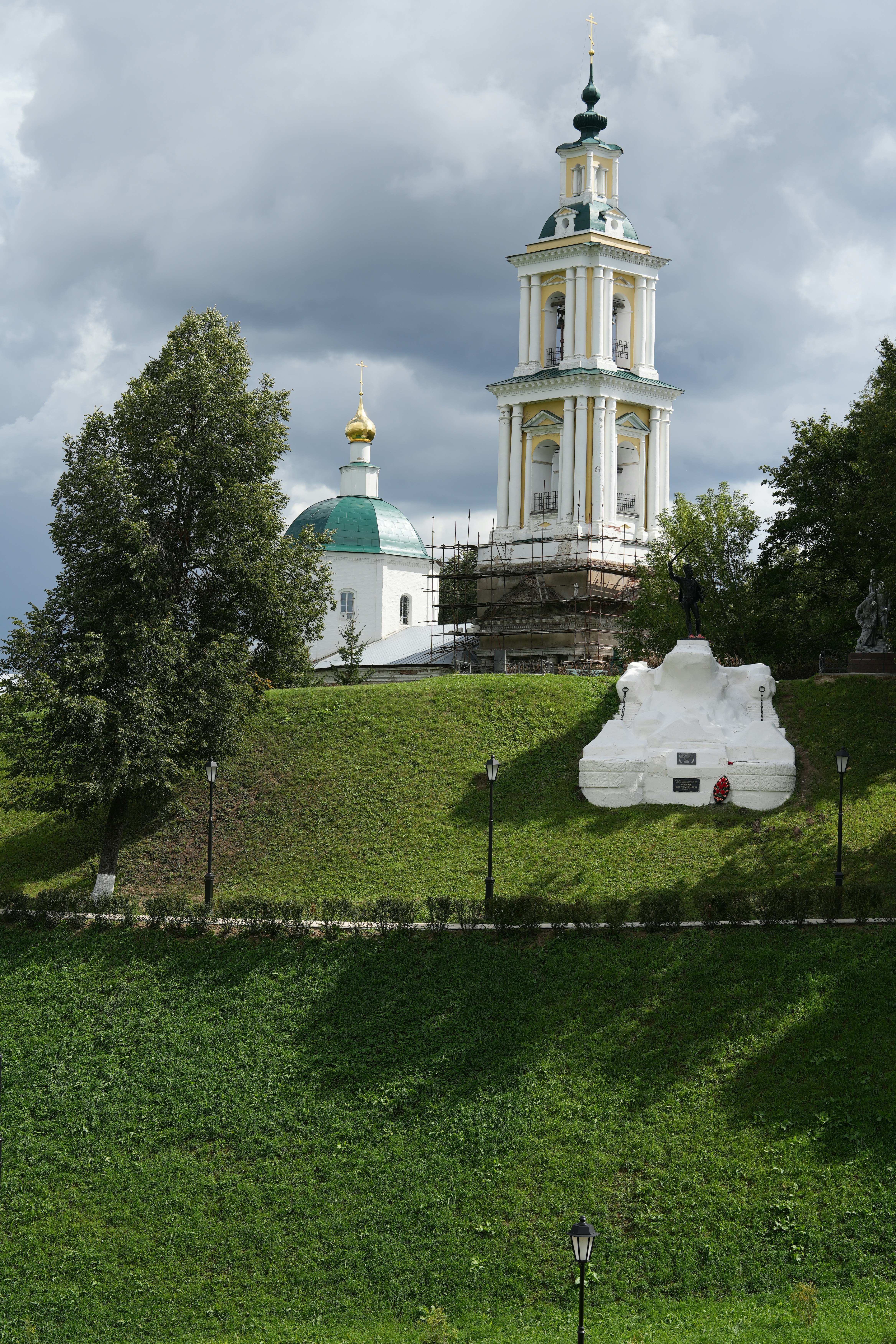 Hilltop Bell Tower Under Renovation Beside a Sculpted Monument