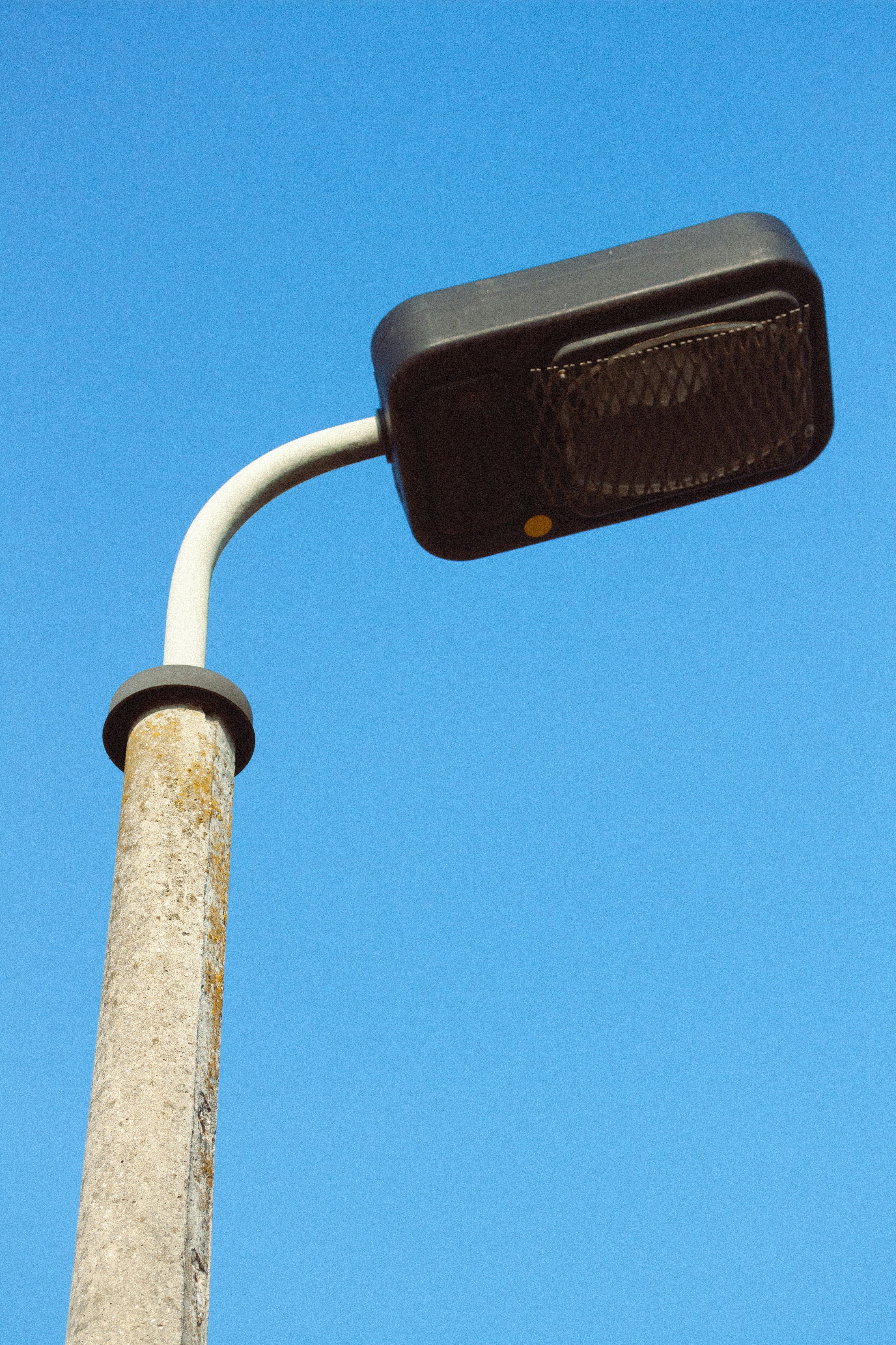 Azure Blue and Steel: The Curved Streetlamp Reaches Toward the Sky