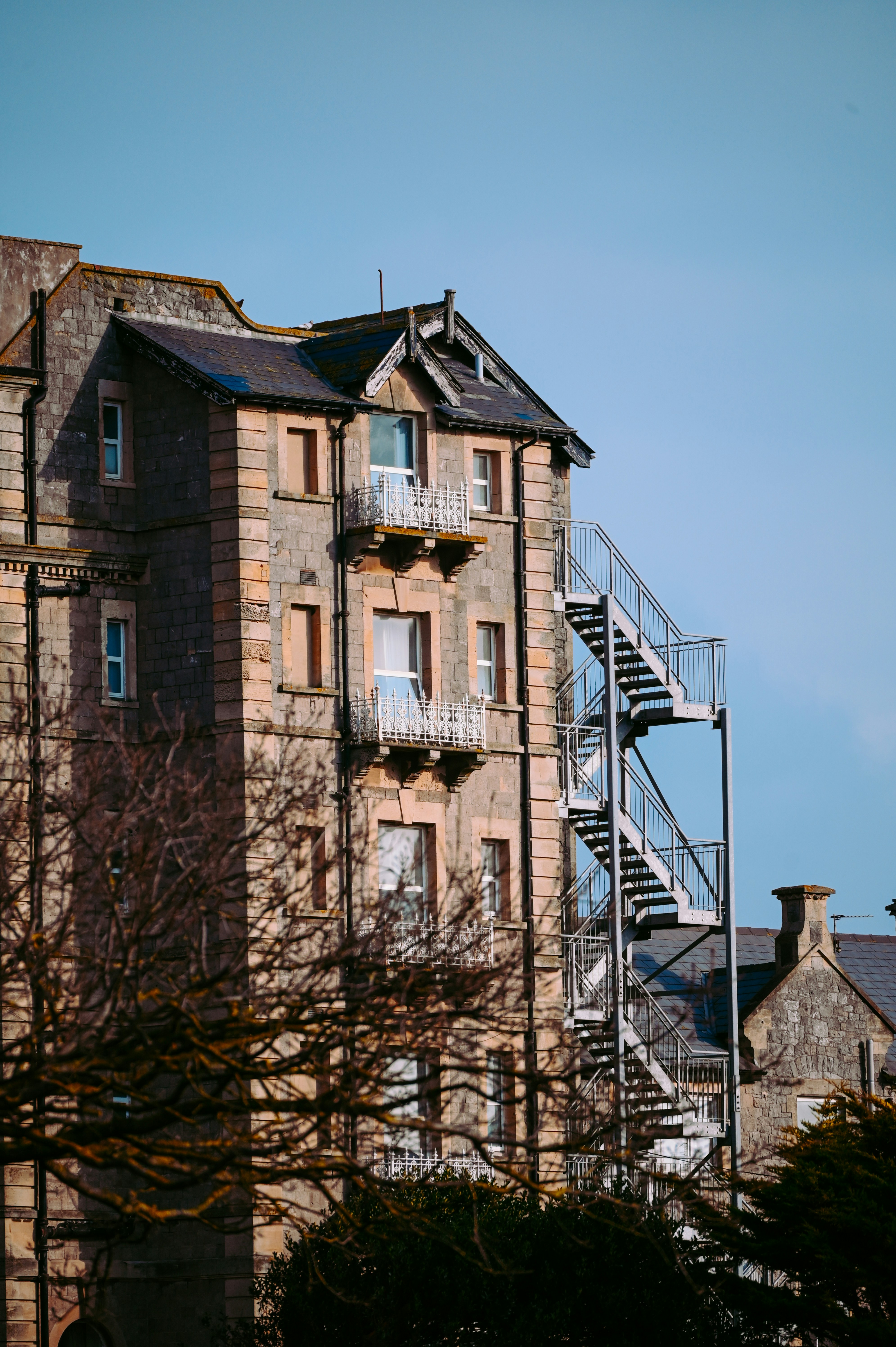 Old stone building with a metal fire escape on a clear day.