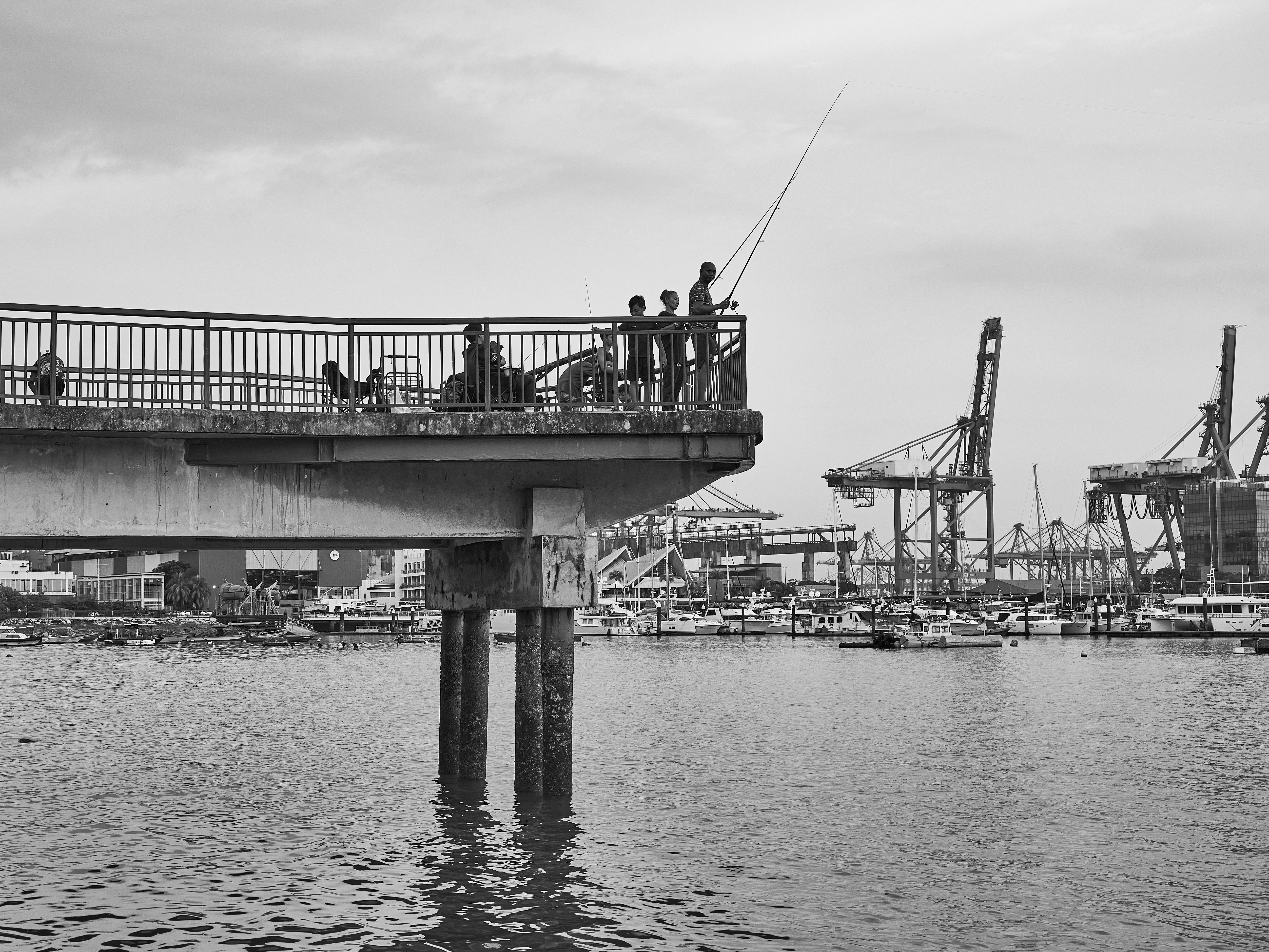 Pierside Vigil: Figures at the Edge Over a Harbor of Cranes
