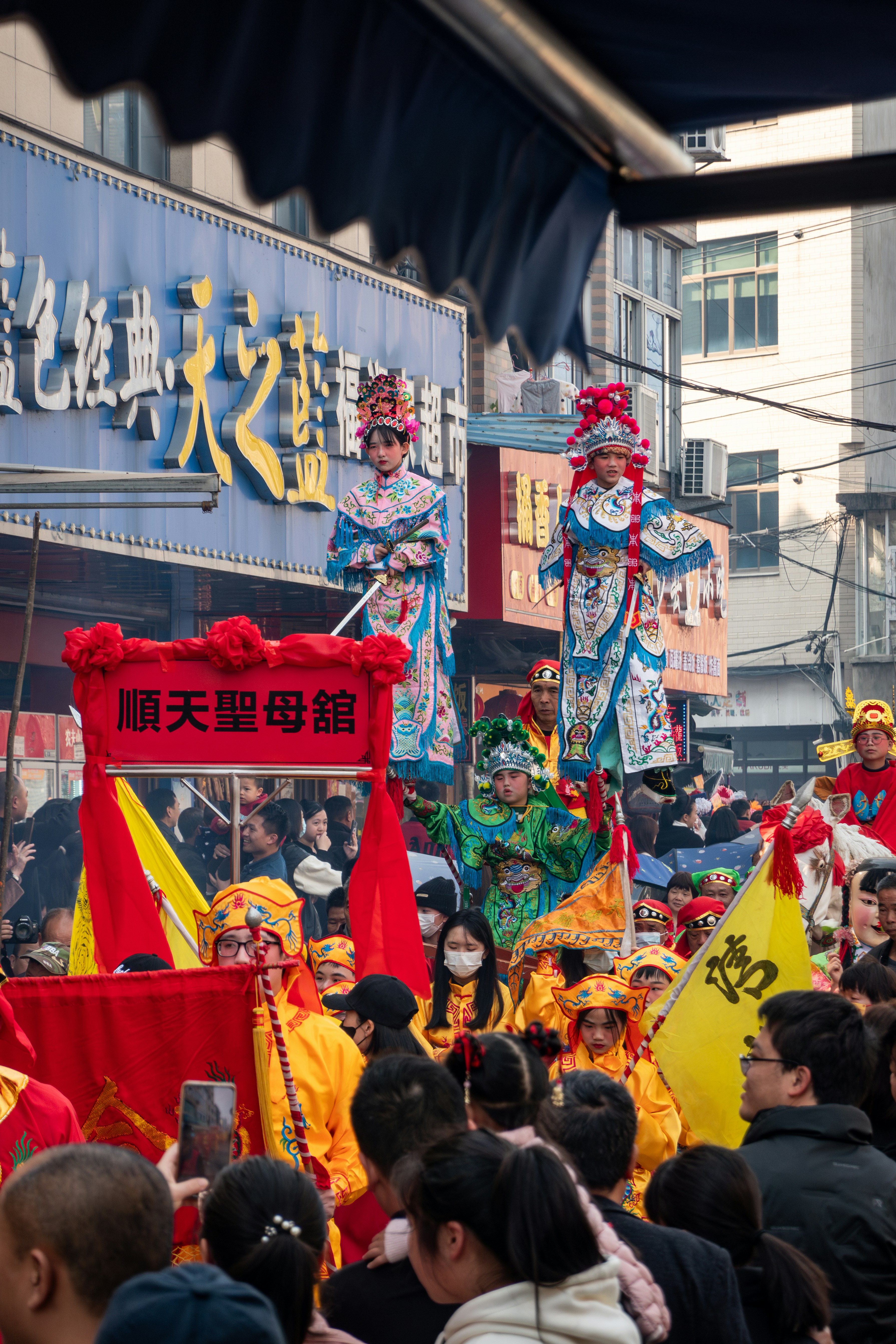 A group of people walking down a street next to tall buildings