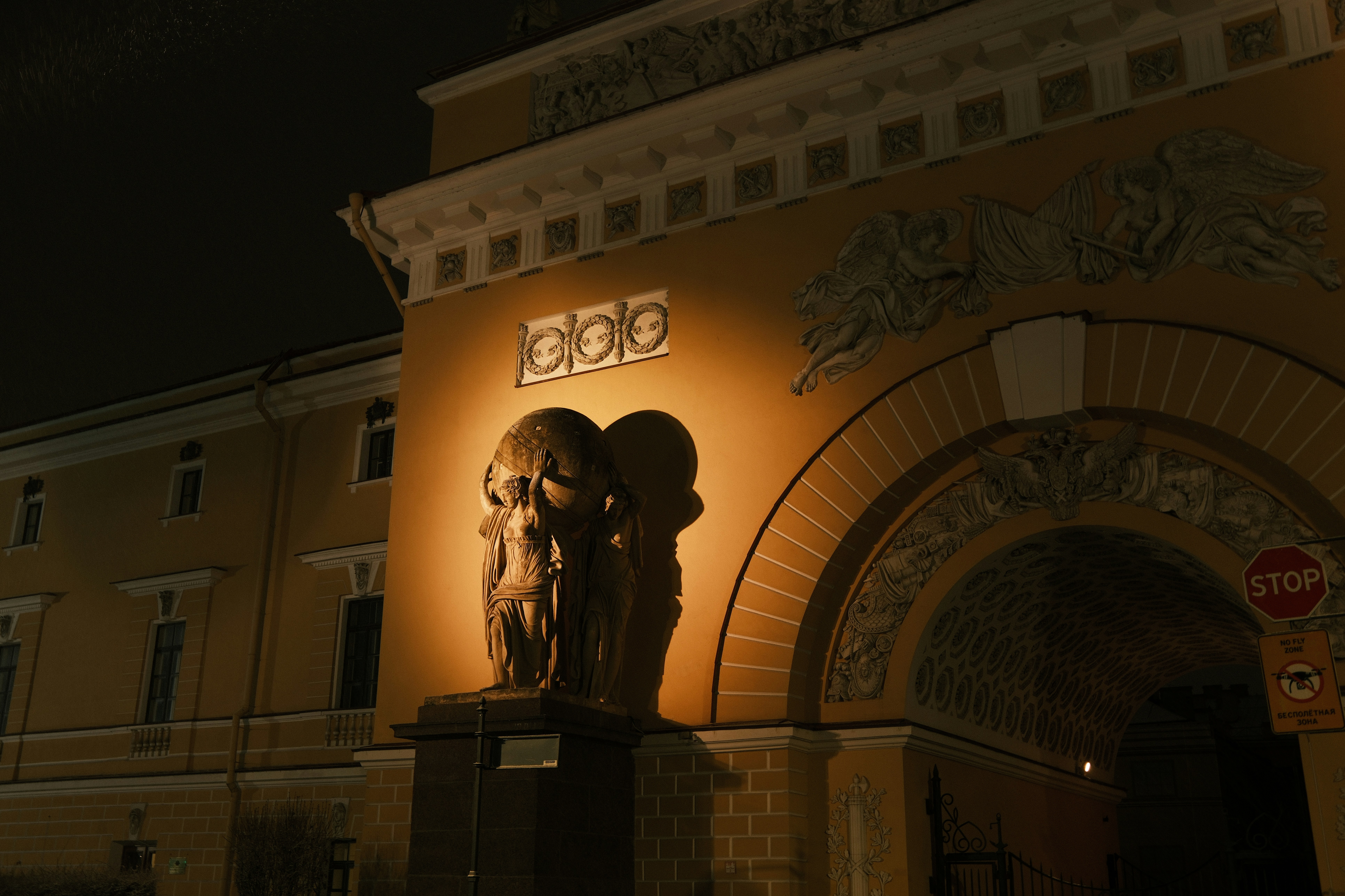 Archway Sentinel: Bronze Figures Bathed in Golden Night Light