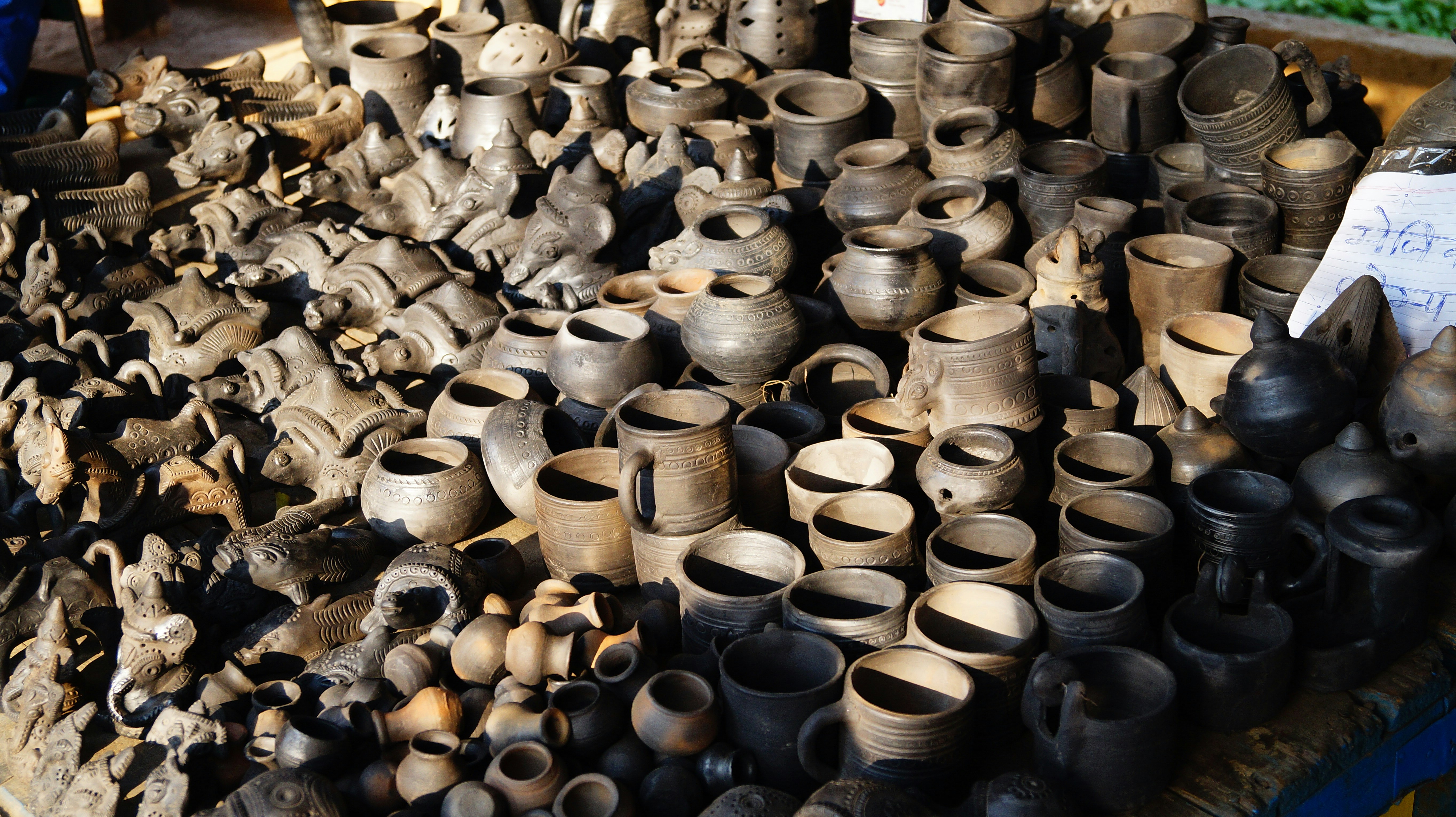 Assortment of clay pots and artifacts in various shapes and sizes, displayed on a market stall.