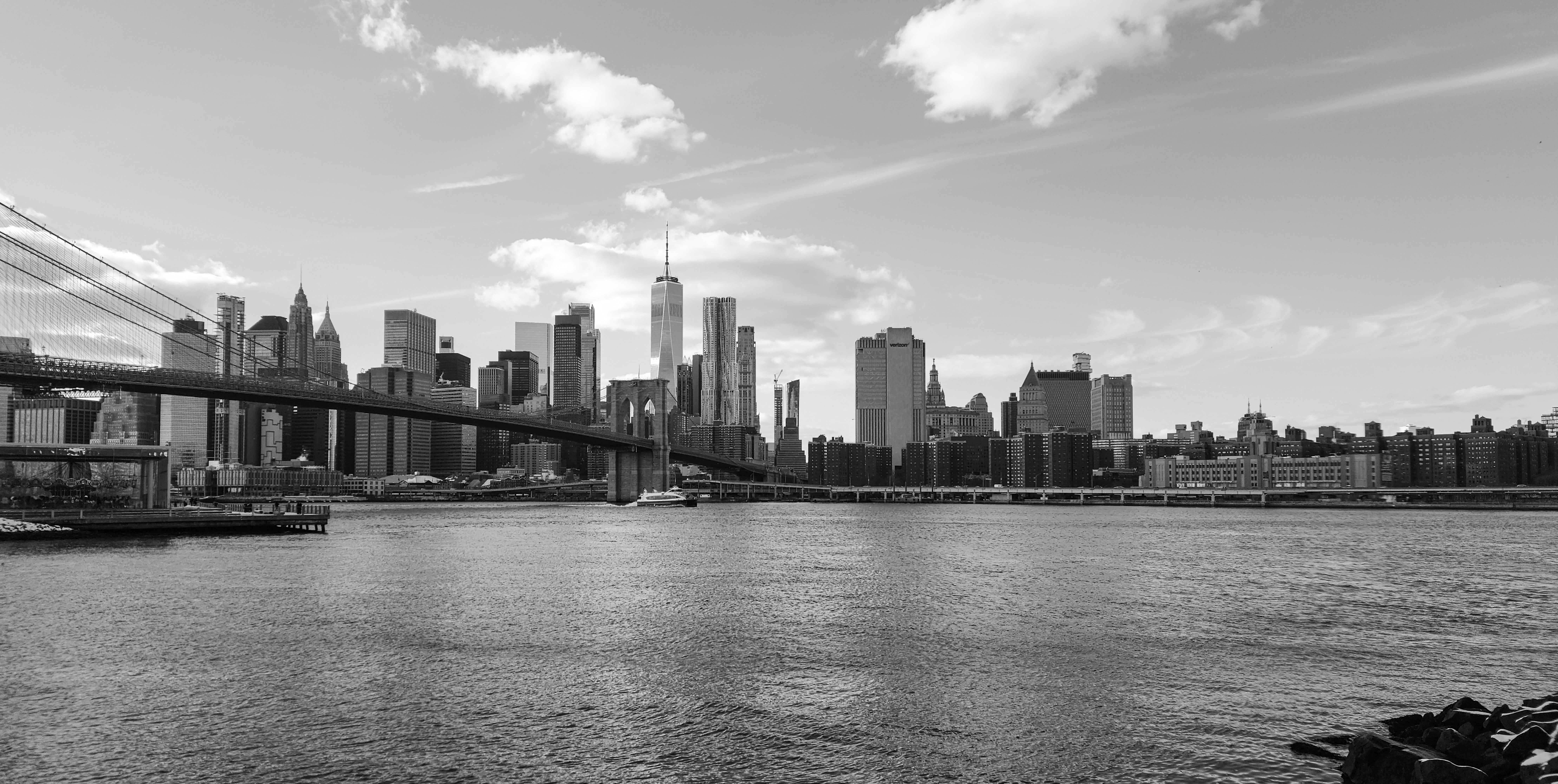 Black-and-white cityscape featuring New York City skyline and Brooklyn Bridge over the East River.