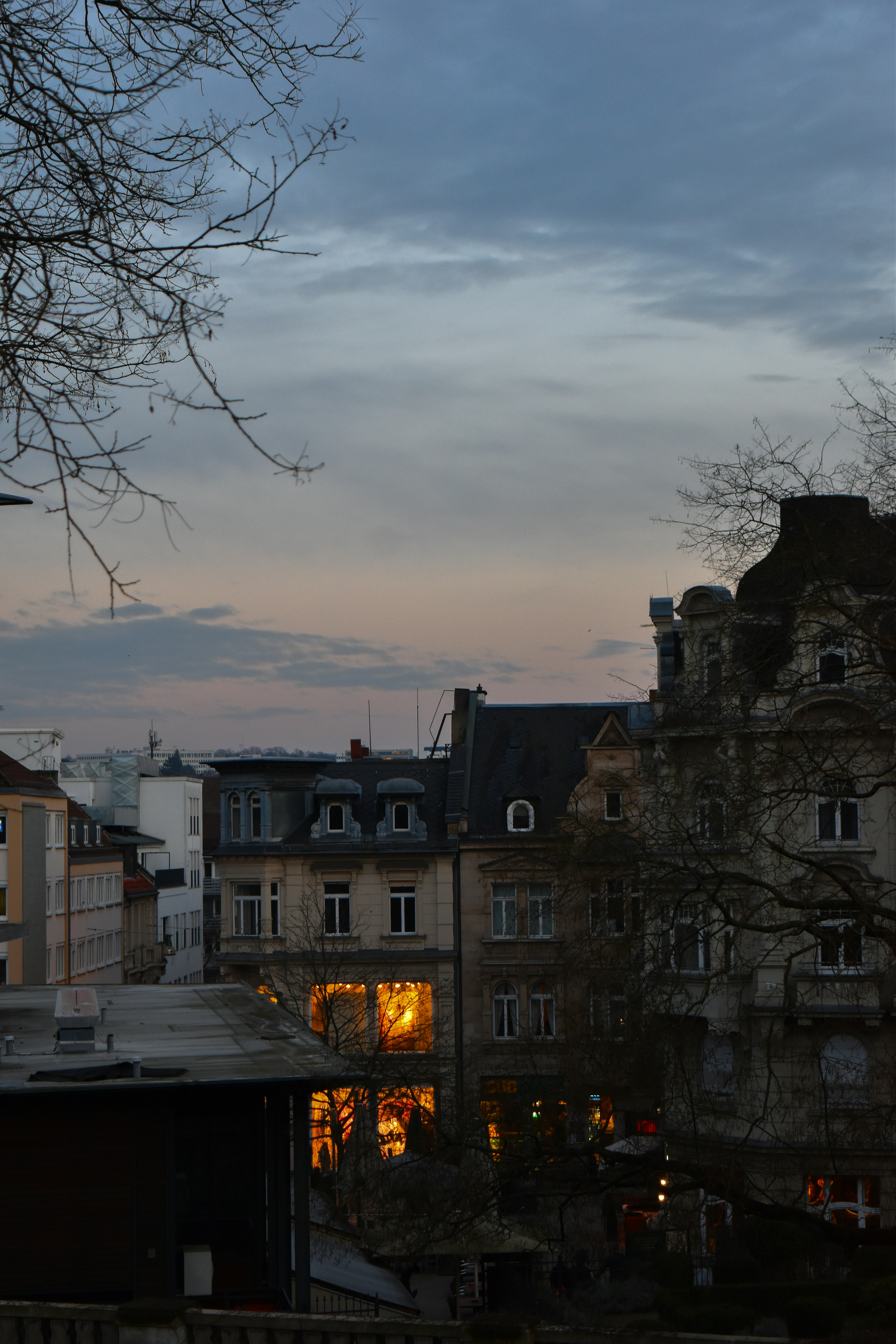 Dusk Glow Through Rooftop Gaps: A Firelit Window in the Quiet Street