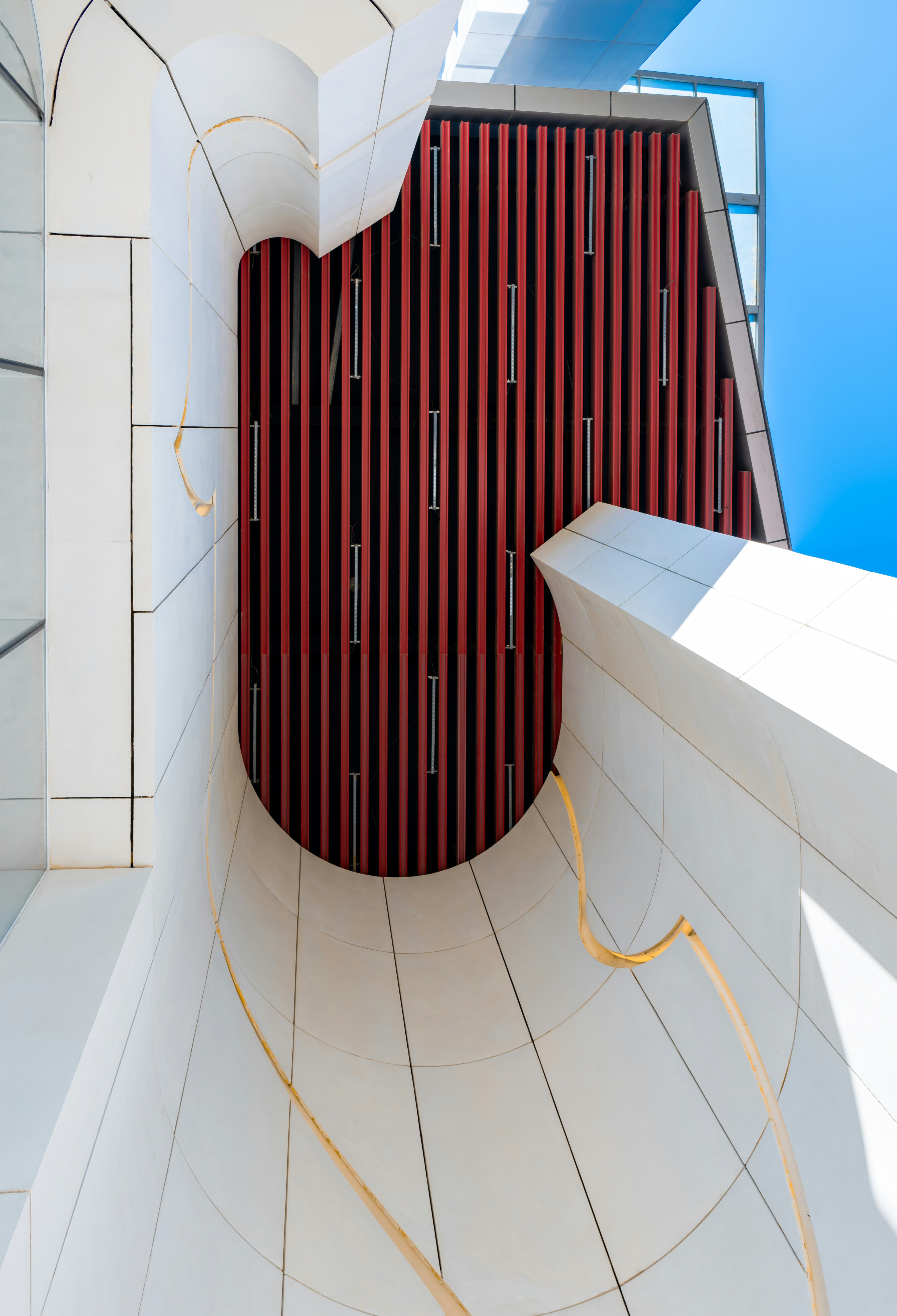 Vertical Red Slats Against White Curves: A Bold Architectural Portrait