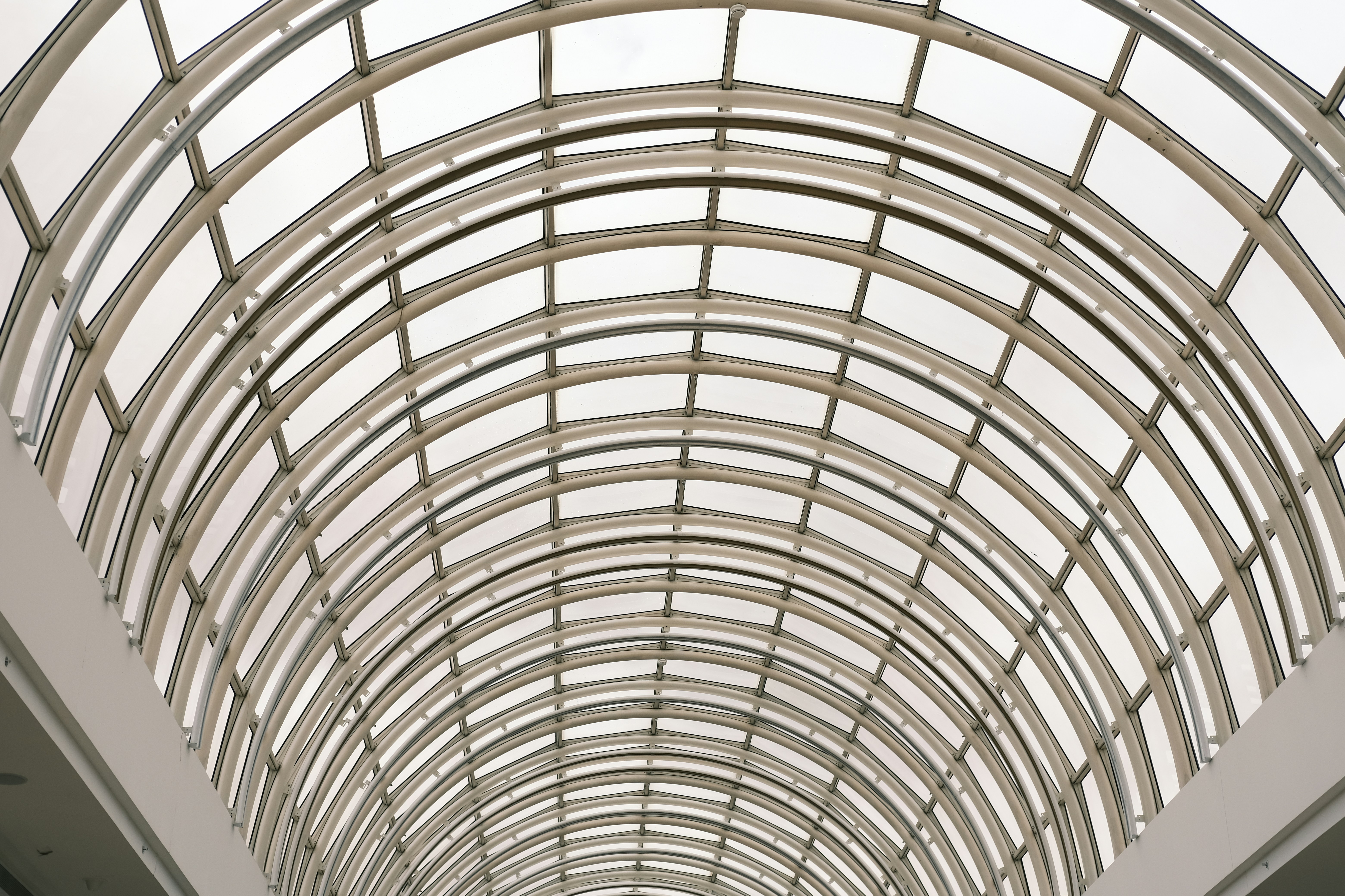 Arched glass ceiling with intricate patterns of lines and curves, softly lit to highlight the contrast between metal and glass.