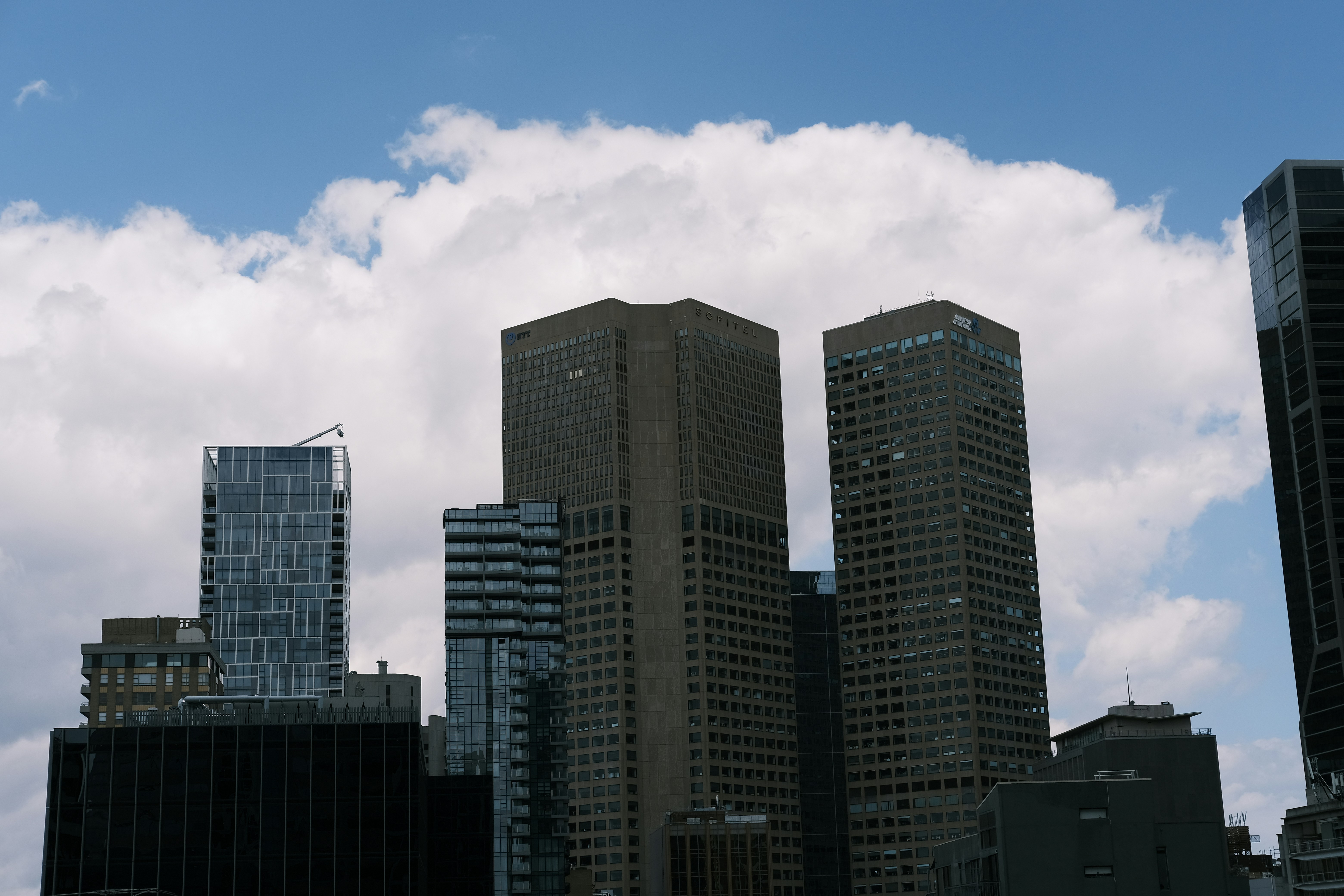 Cluster of modern skyscrapers against a bright blue sky with fluffy white clouds.