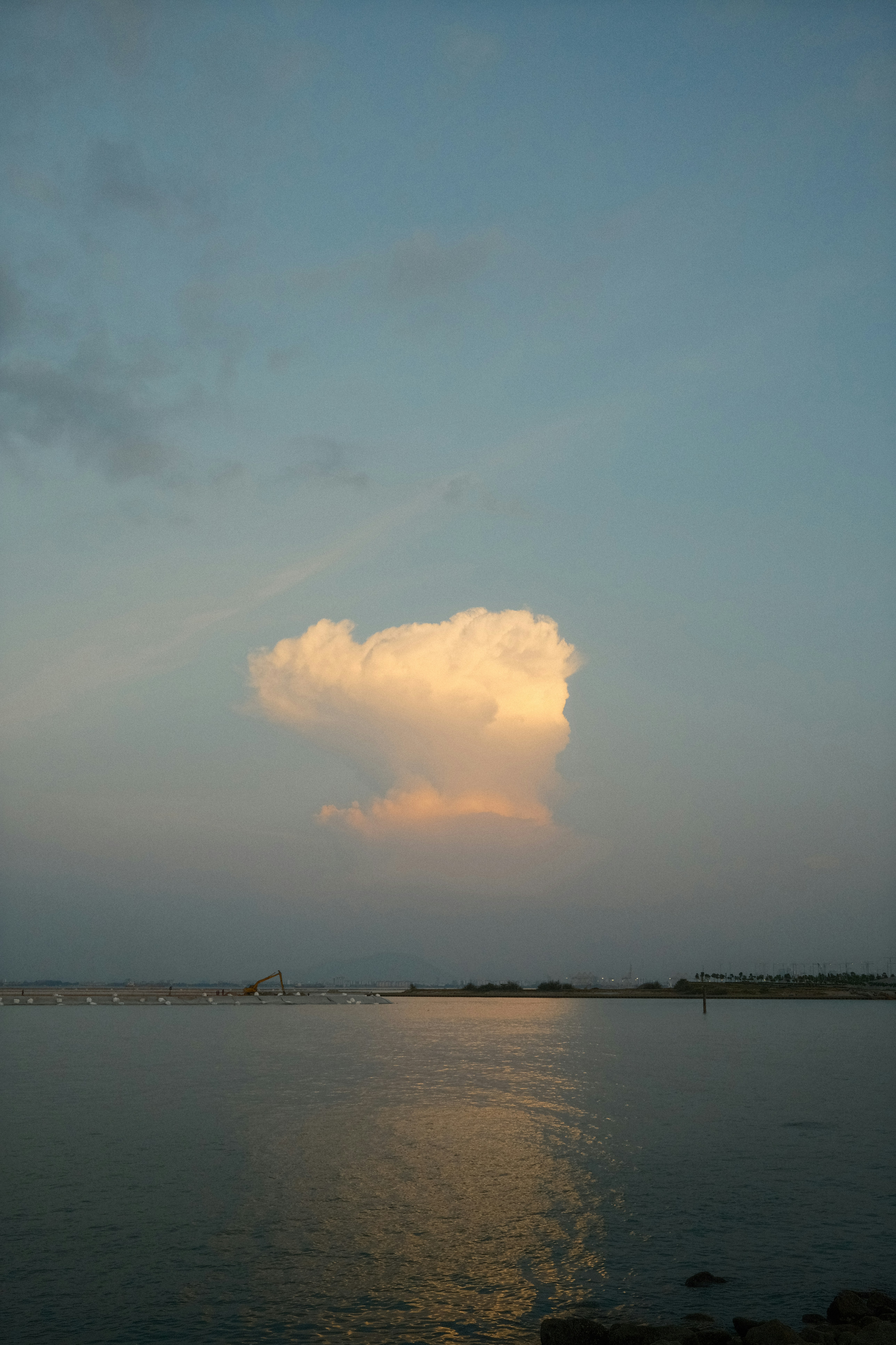 A cloud is floating in the sky over a body of water