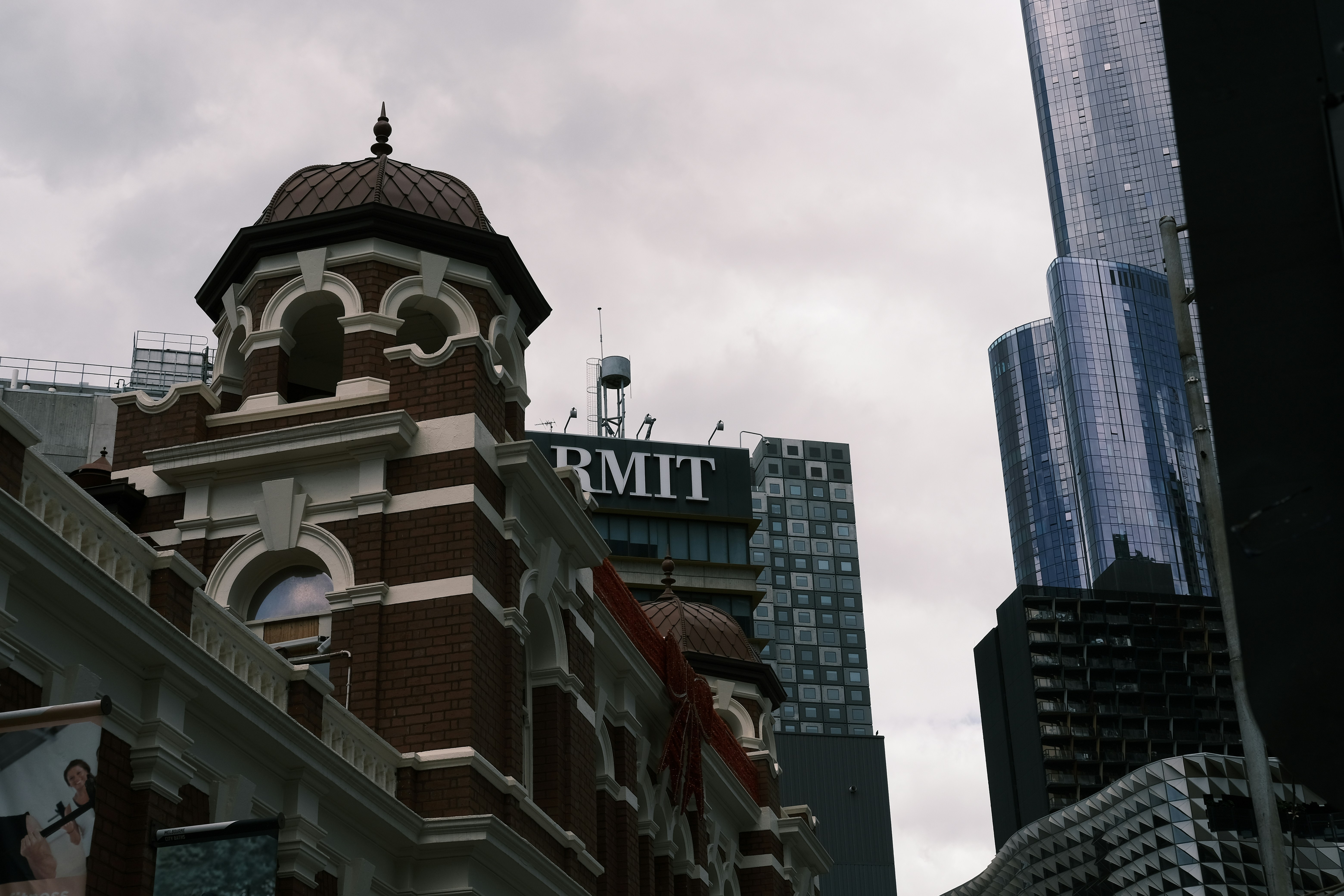 Historical brick architecture contrasts with sleek skyscrapers beneath a cloudy sky.