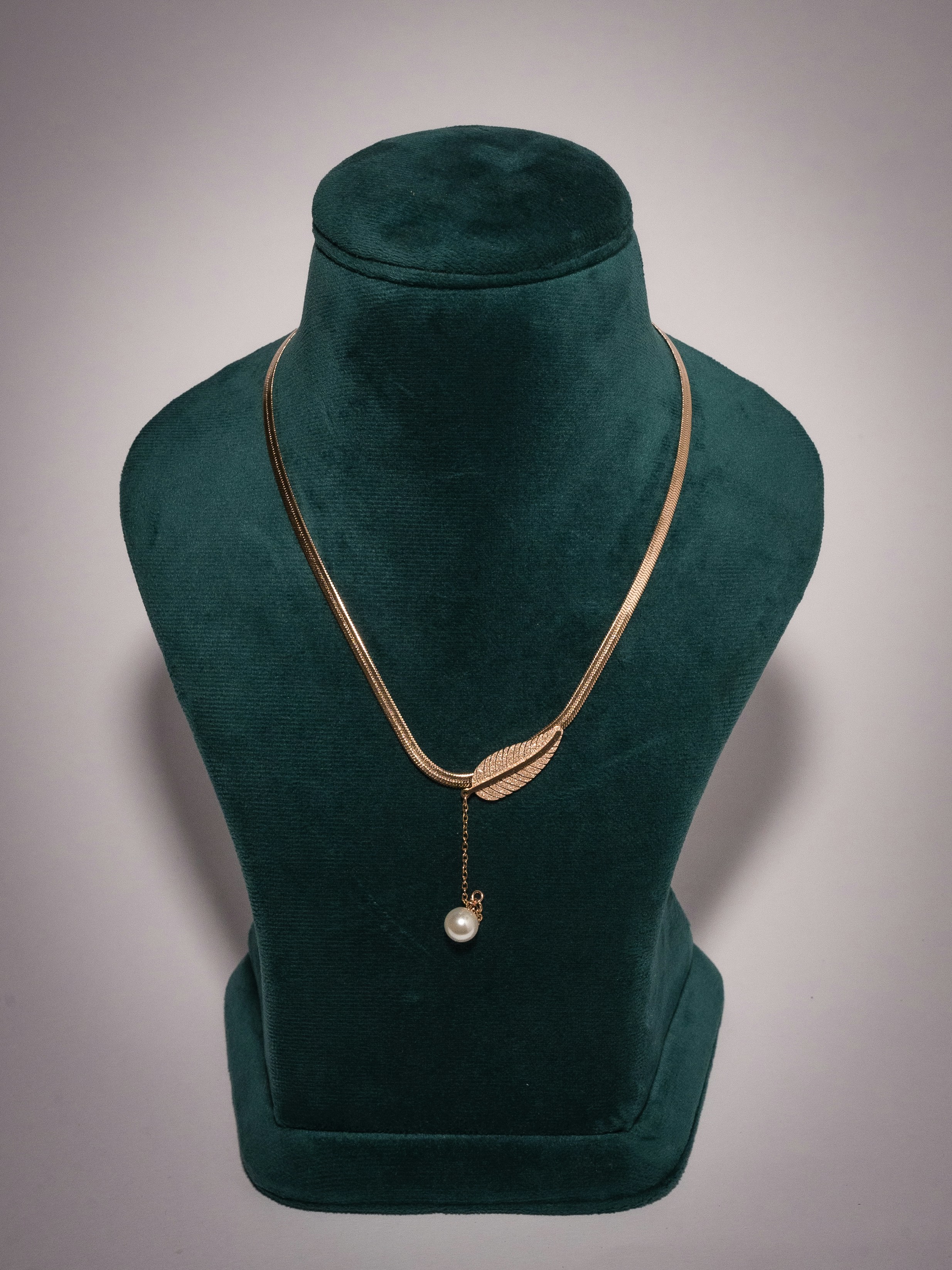 A green mannequin with a necklace on it
