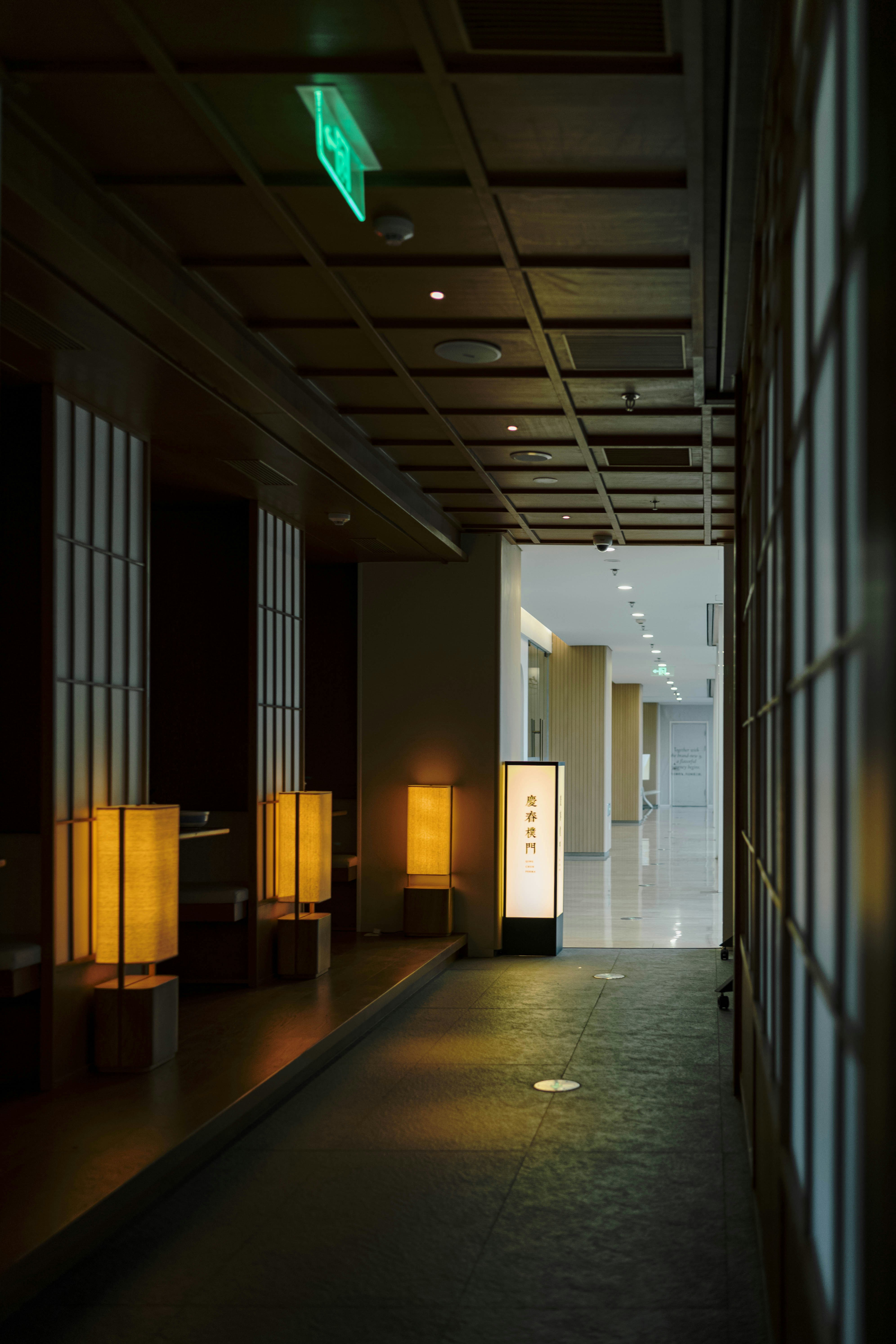 A dimly lit hallway with a green sign on the wall photo – Free Floor ...