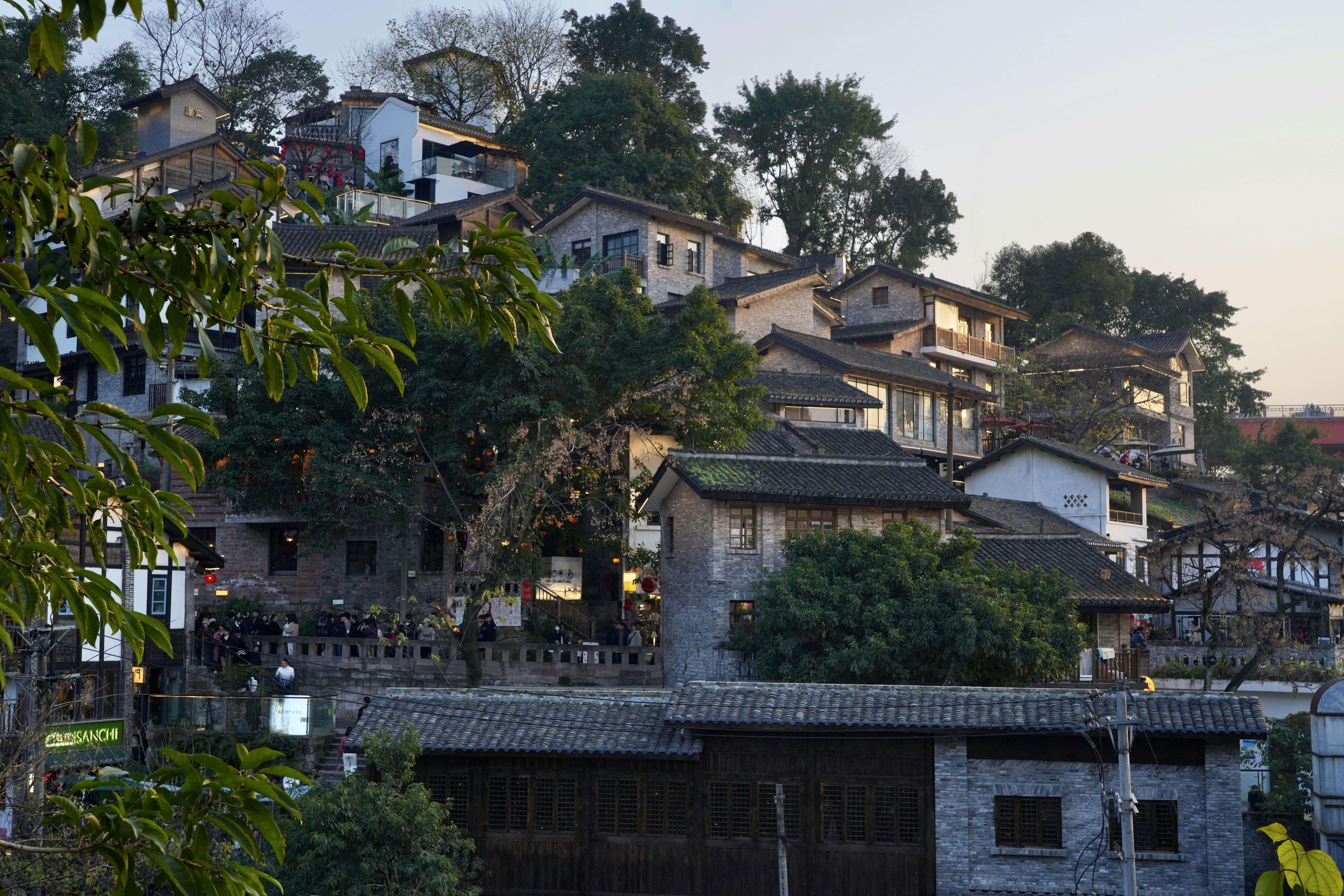 Cluster of hillside homes surrounded by lush greenery at dawn.