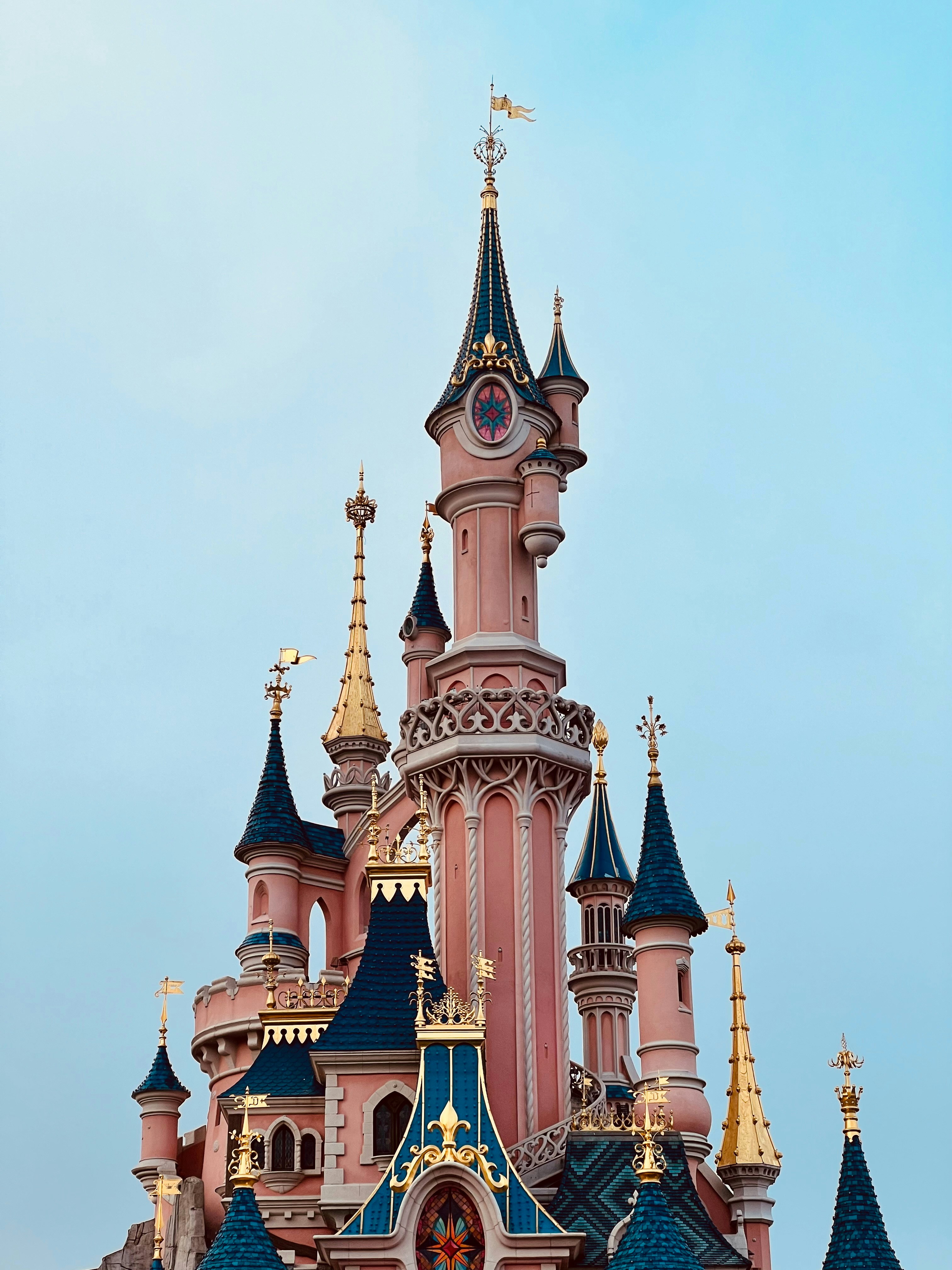 A pink and blue castle with a clock on it photo – Free Disneyland paris ...