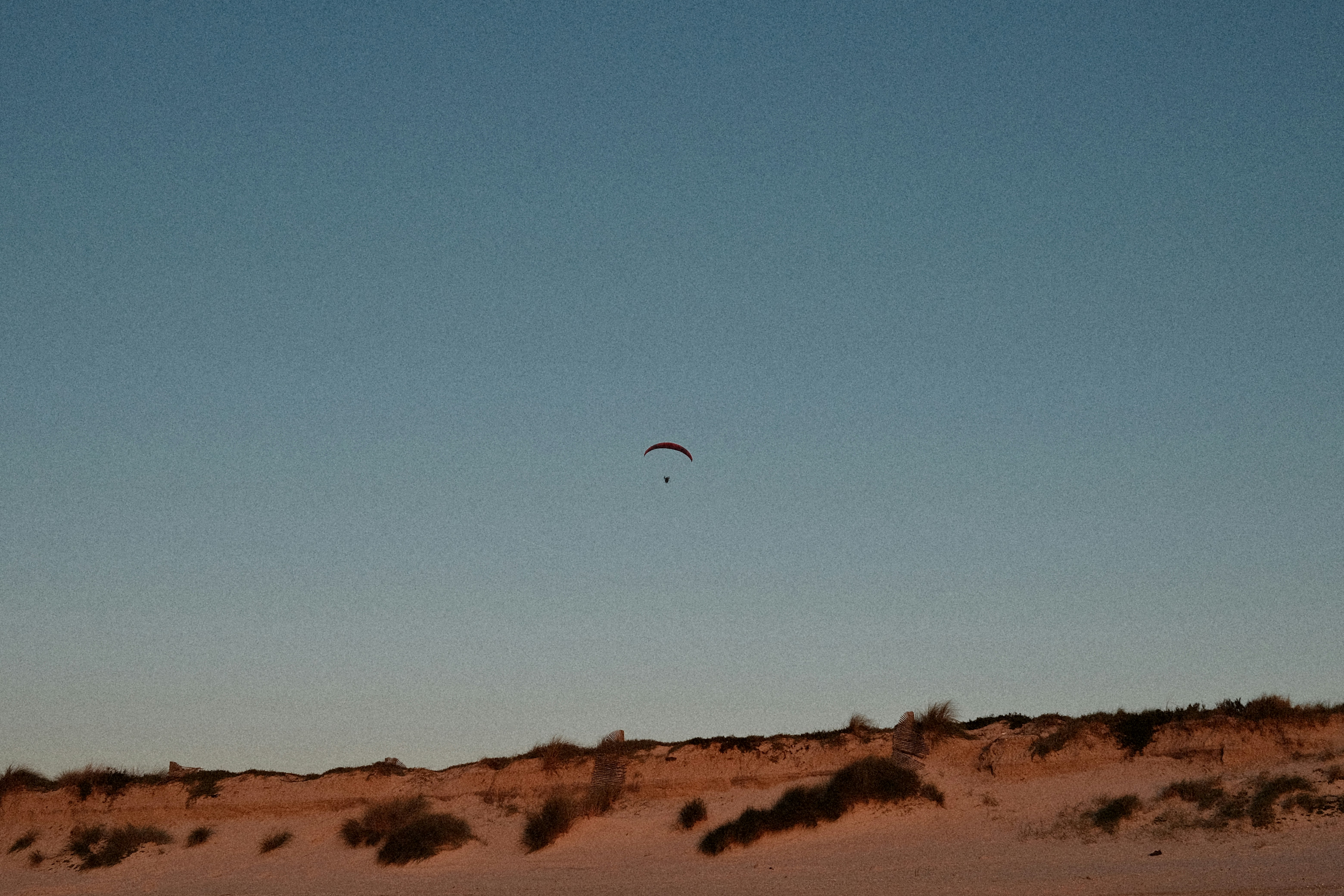 Dune Kite: A Lone Parachute Soars Over Sand Ridges