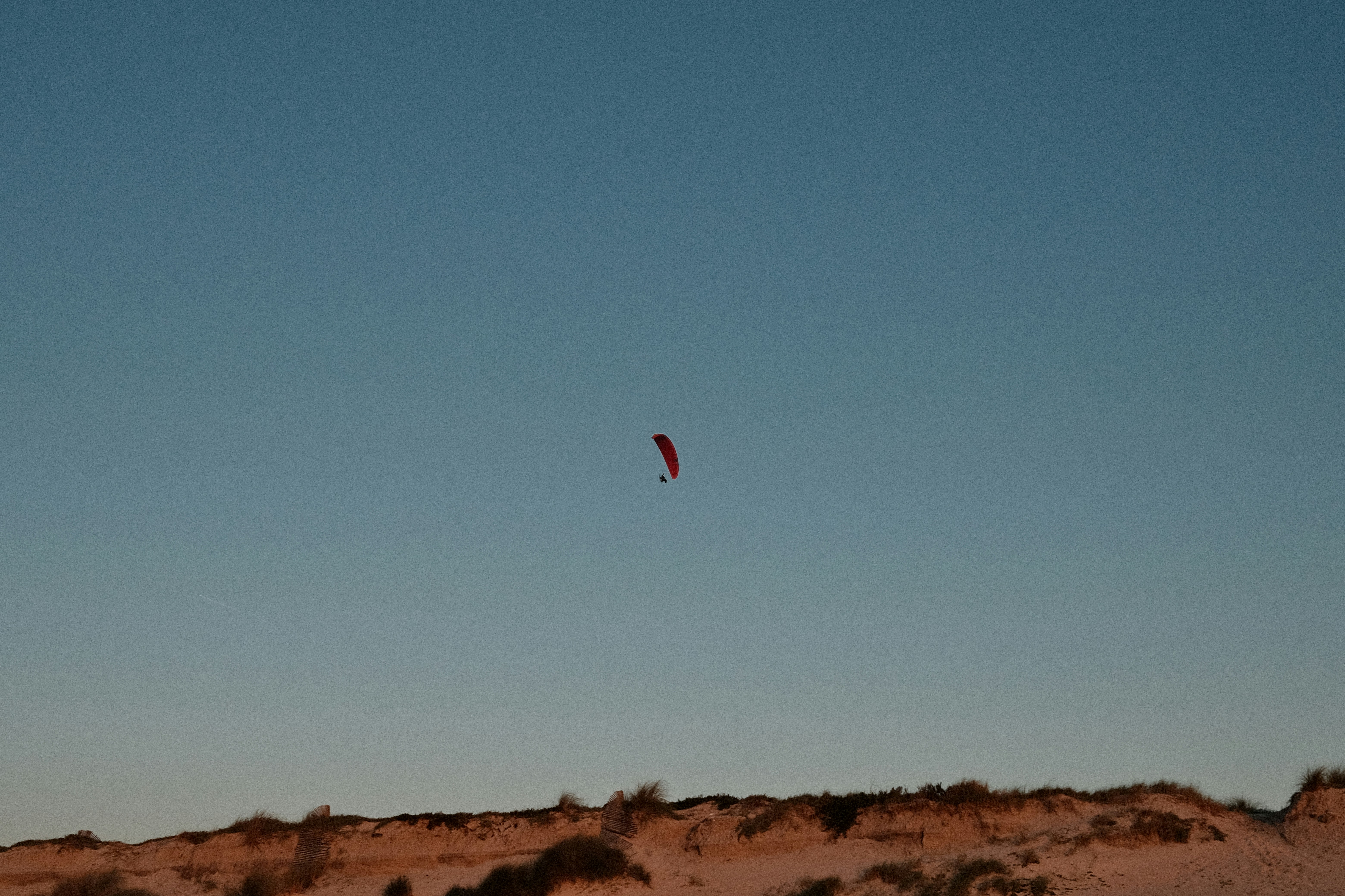 Scarlet Kite Drifts Over a Quiet Desert Dune