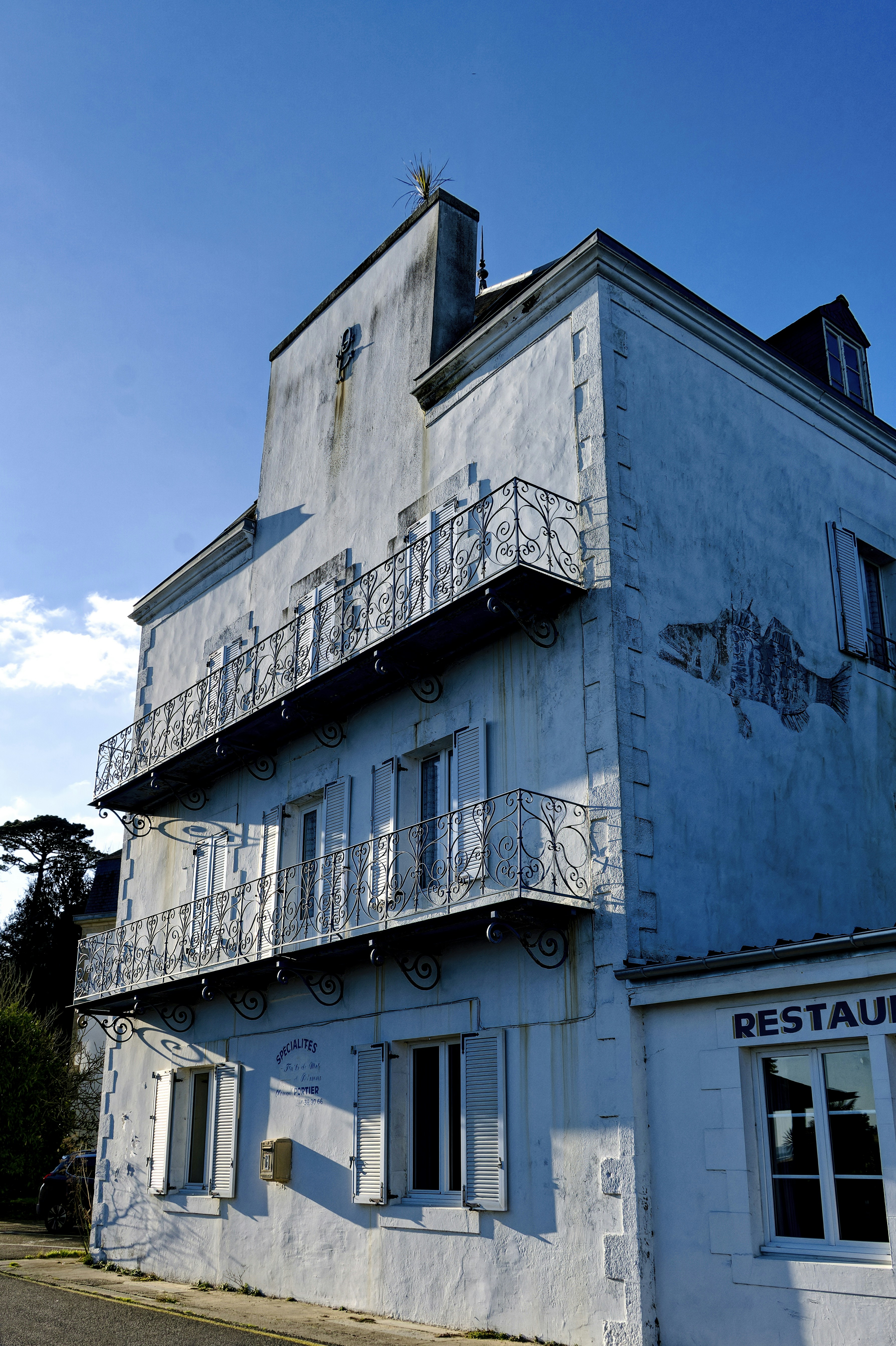 Three-Story Blue Facade: Wrought-Iron Balconies in Quiet Sun