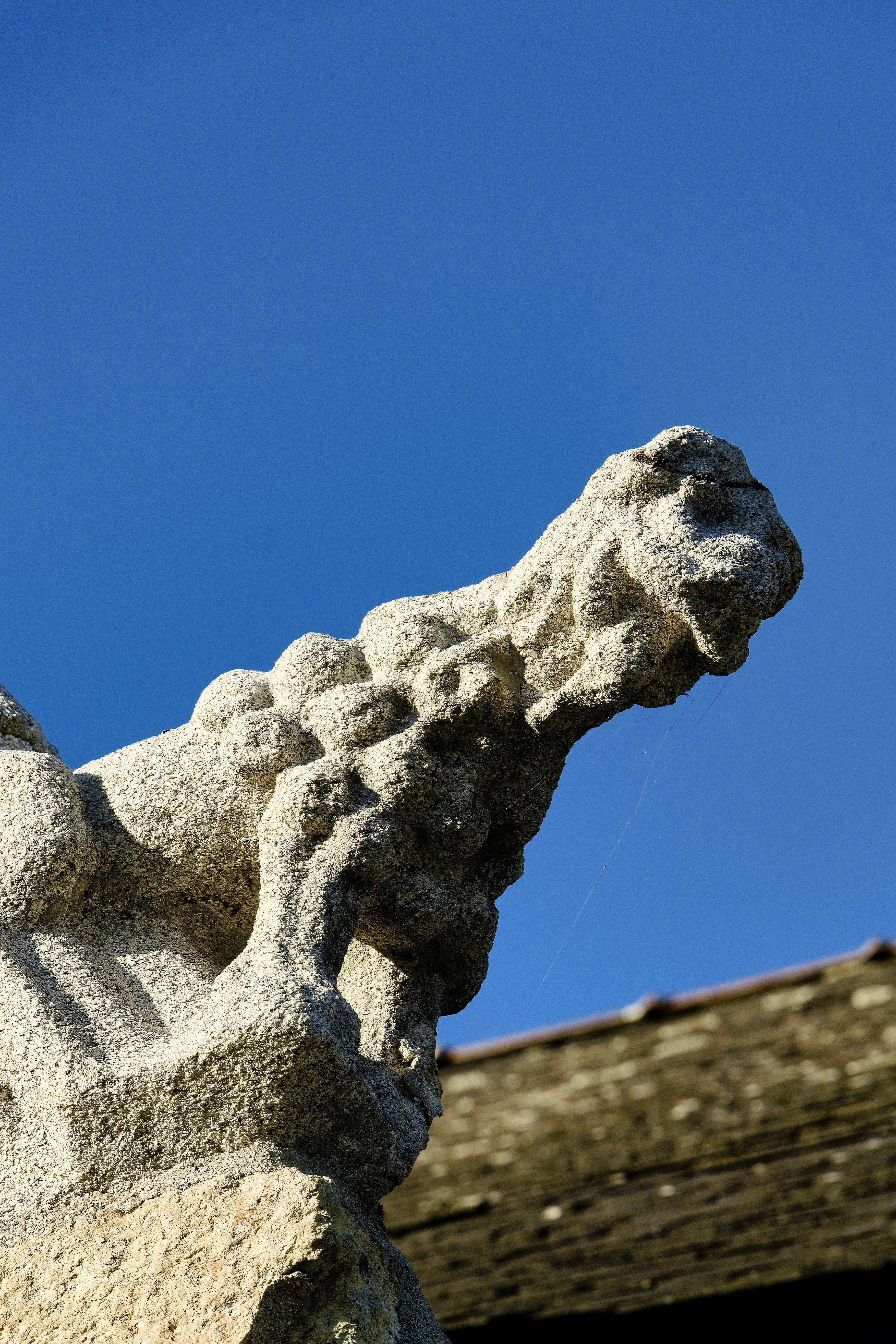 Azure Sky over Weathered Gargoyle: A Stone Sentinel Reaches Skyward