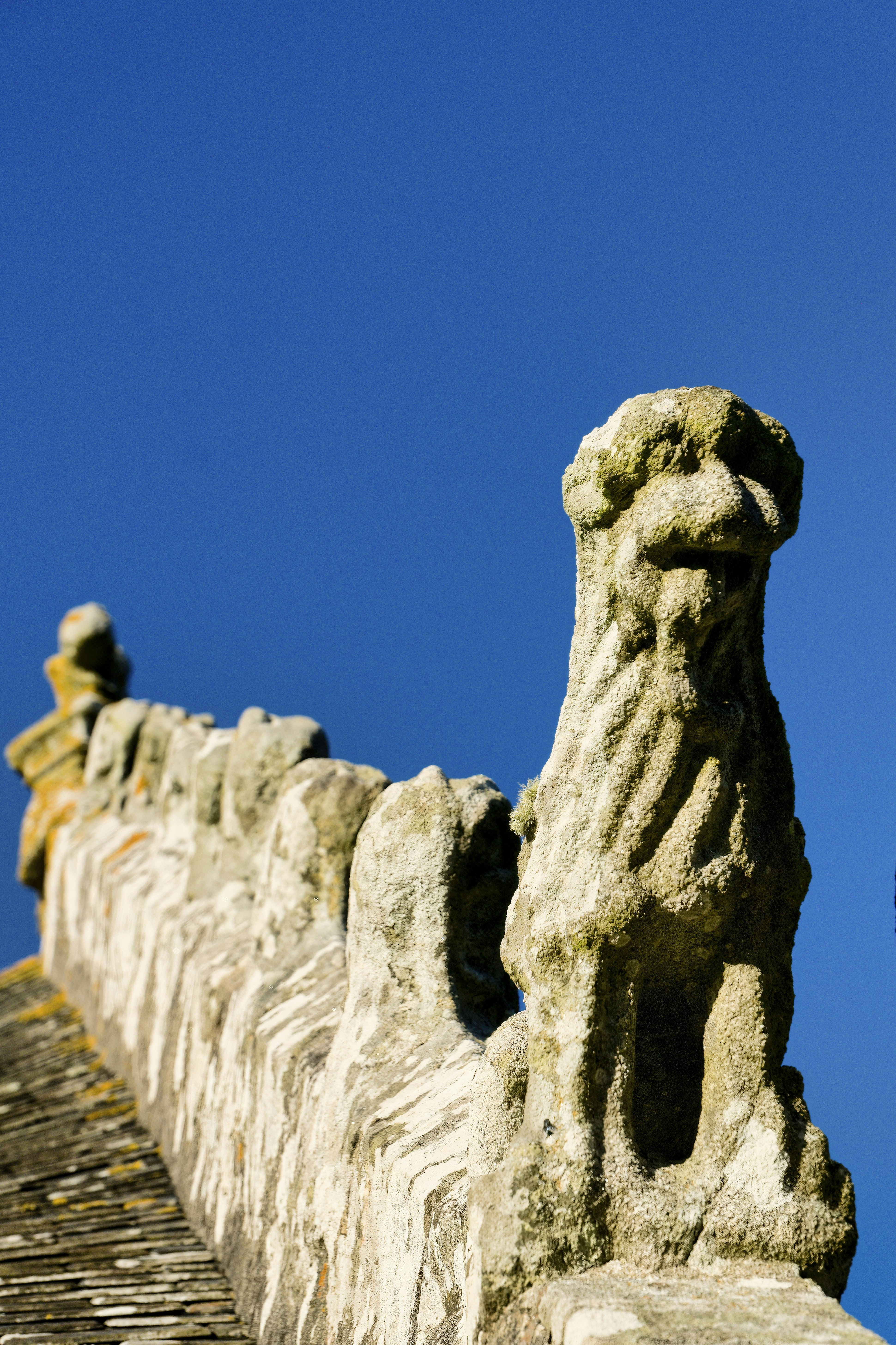 Weathered gargoyle guardians along a sunlit cobalt ridge
