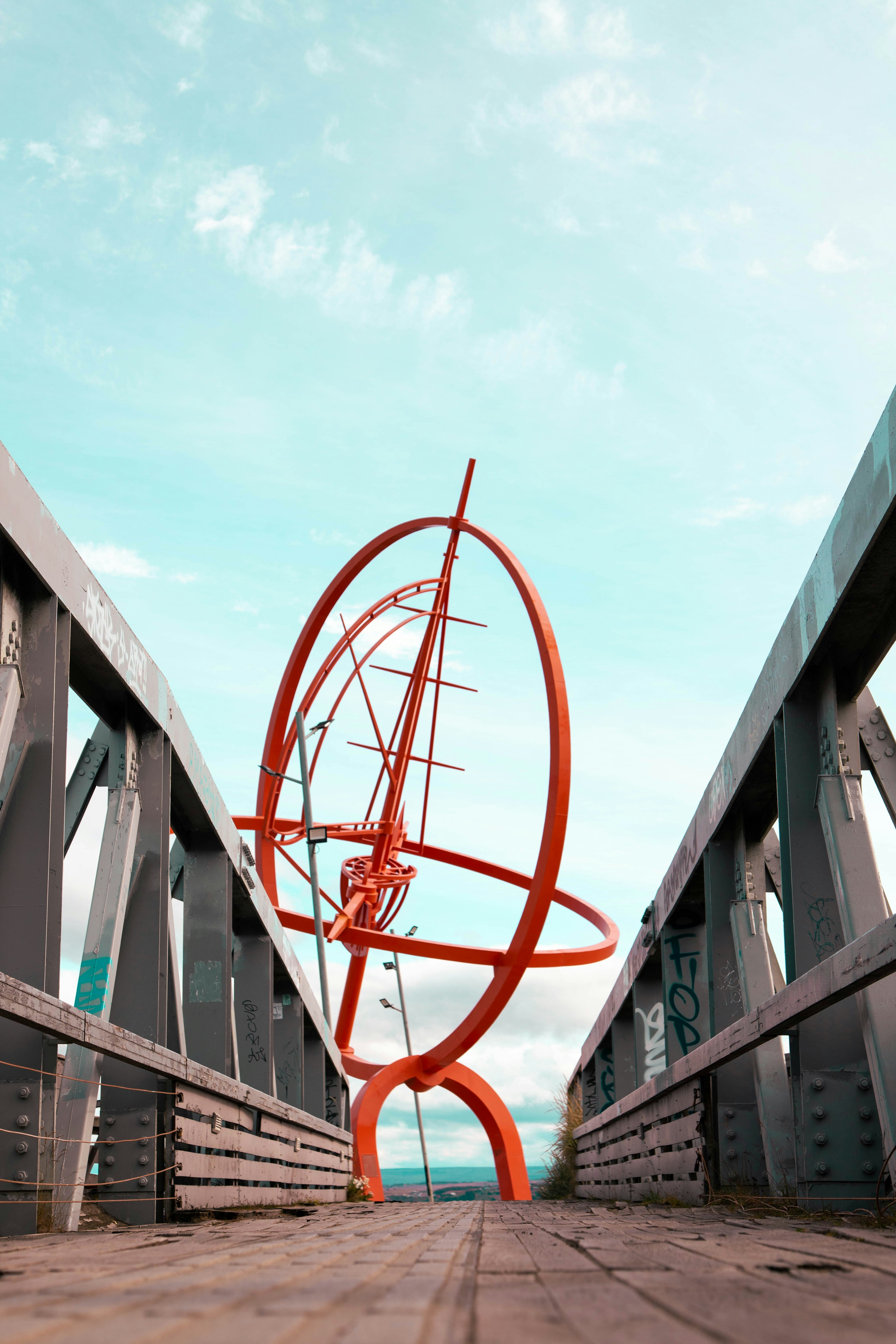 Red Arch in Transit: A Bridge-Top Sculpture Framed by Rails