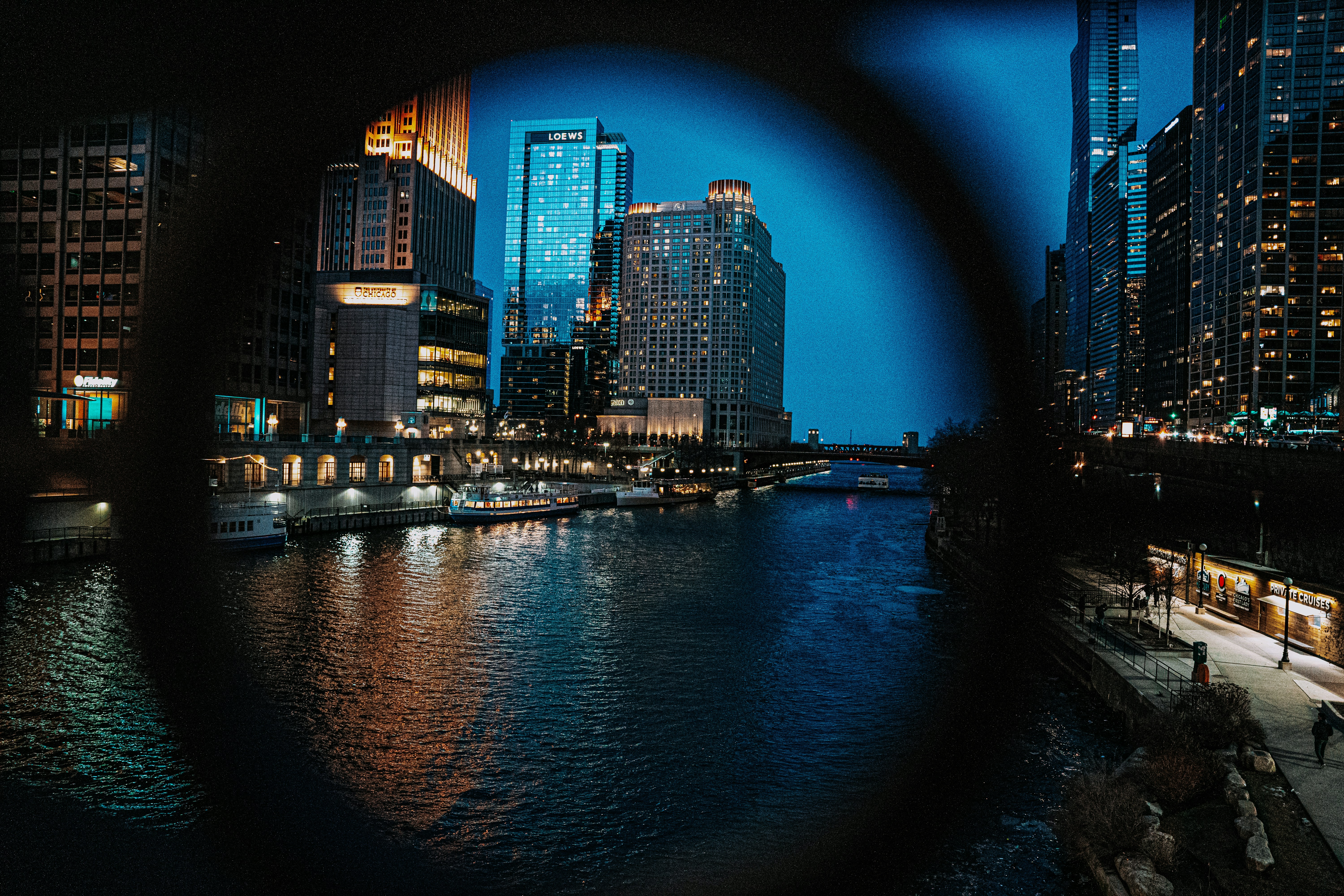 City skyline at twilight with buildings and river reflecting vibrant lights.