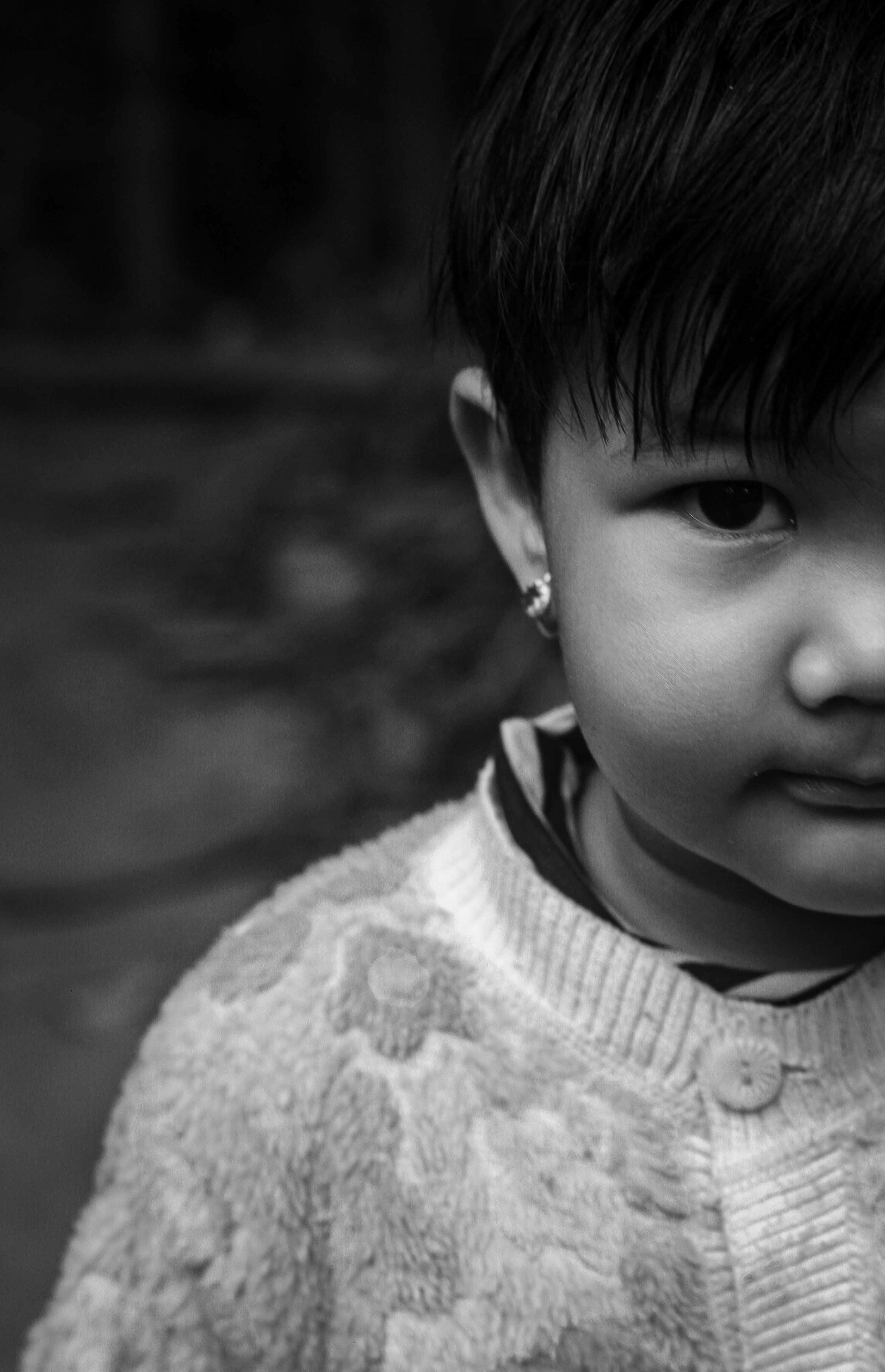 A close-up of a child's face, capturing a moment of curiosity and contemplation in monochrome tones.