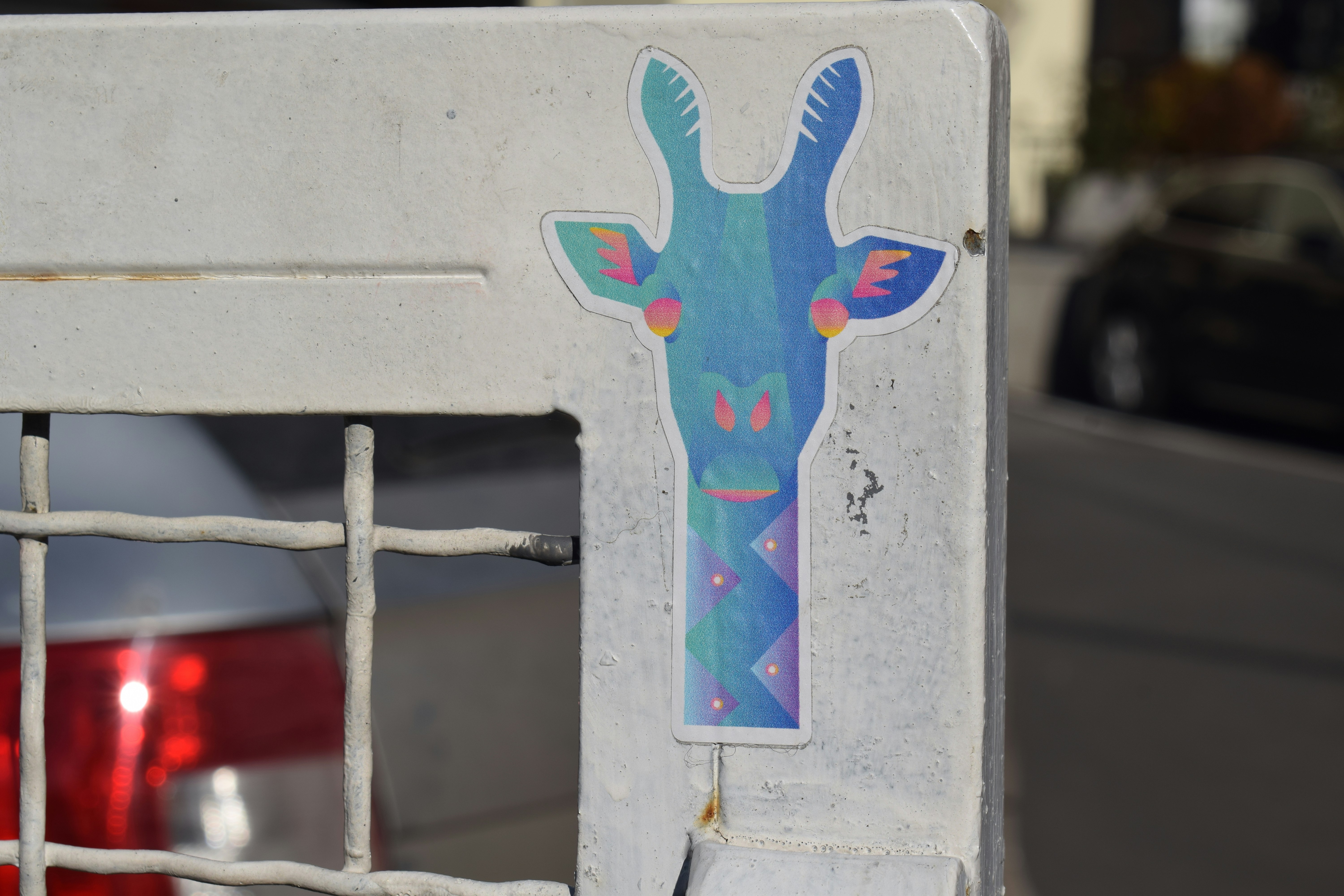 Colorful Giraffe Sticker on a Metal Barrier Overlooking a Street