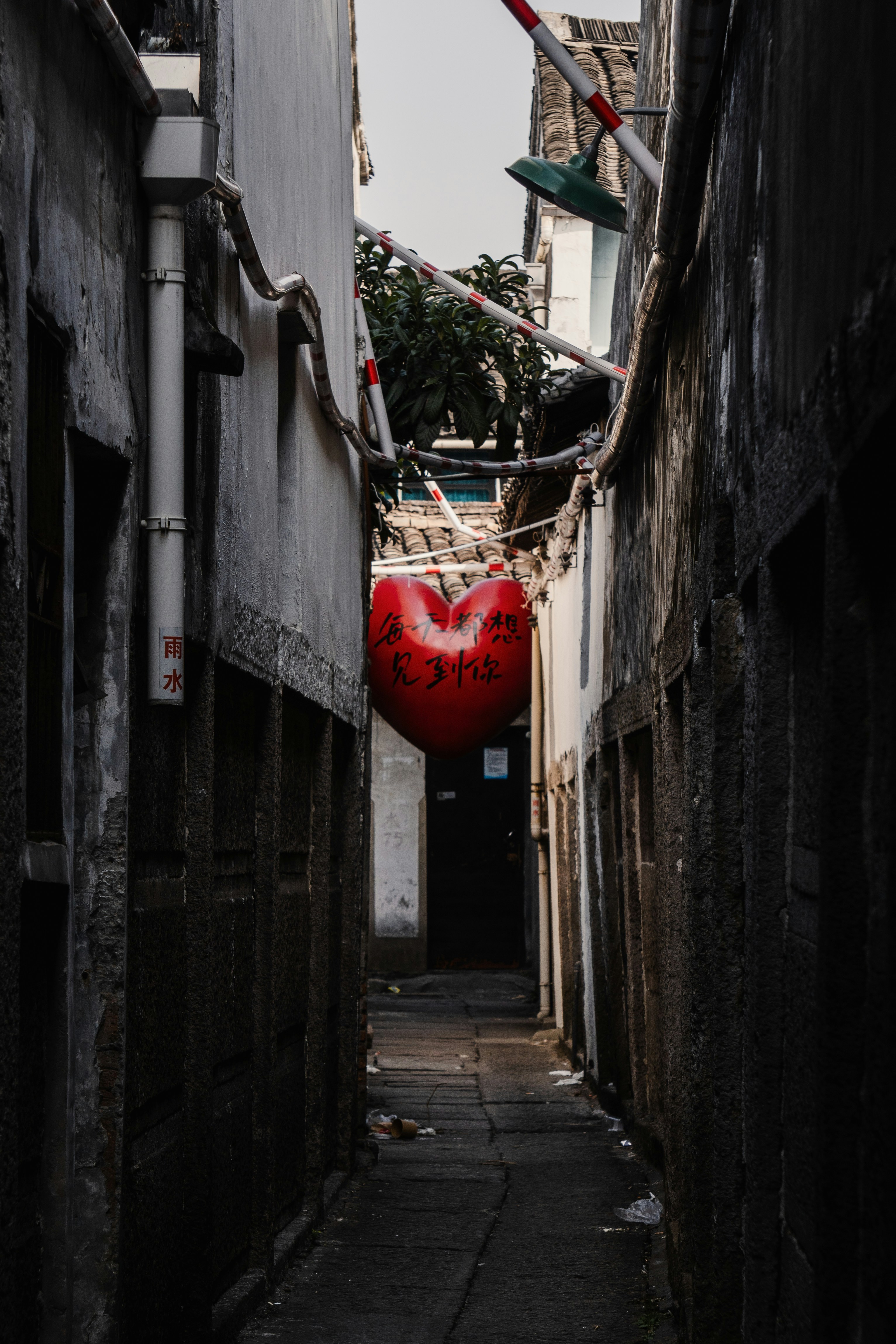 A narrow alley way with a red heart hanging from the side
