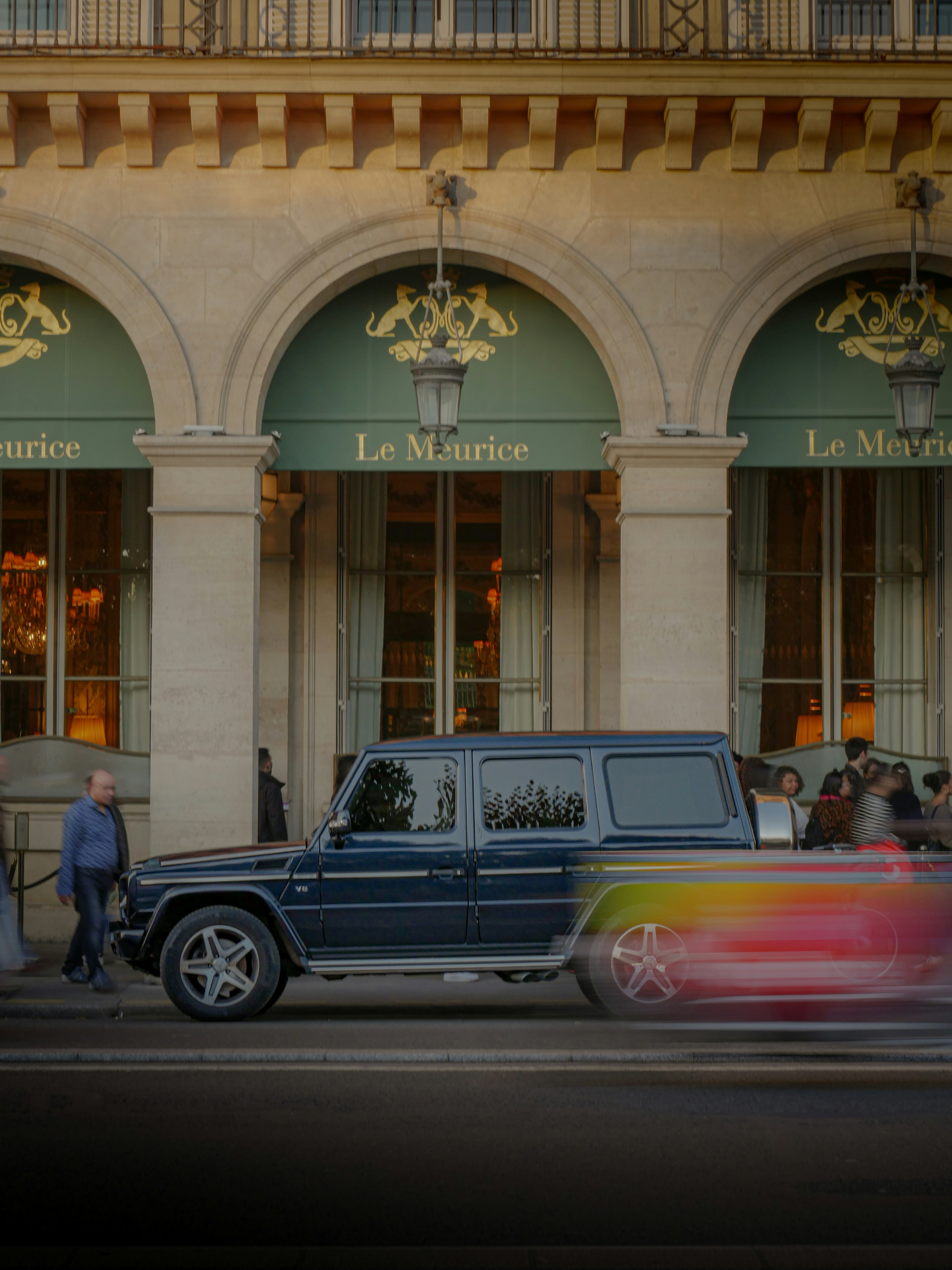 A car driving past a tall building with a clock on it's side photo ...