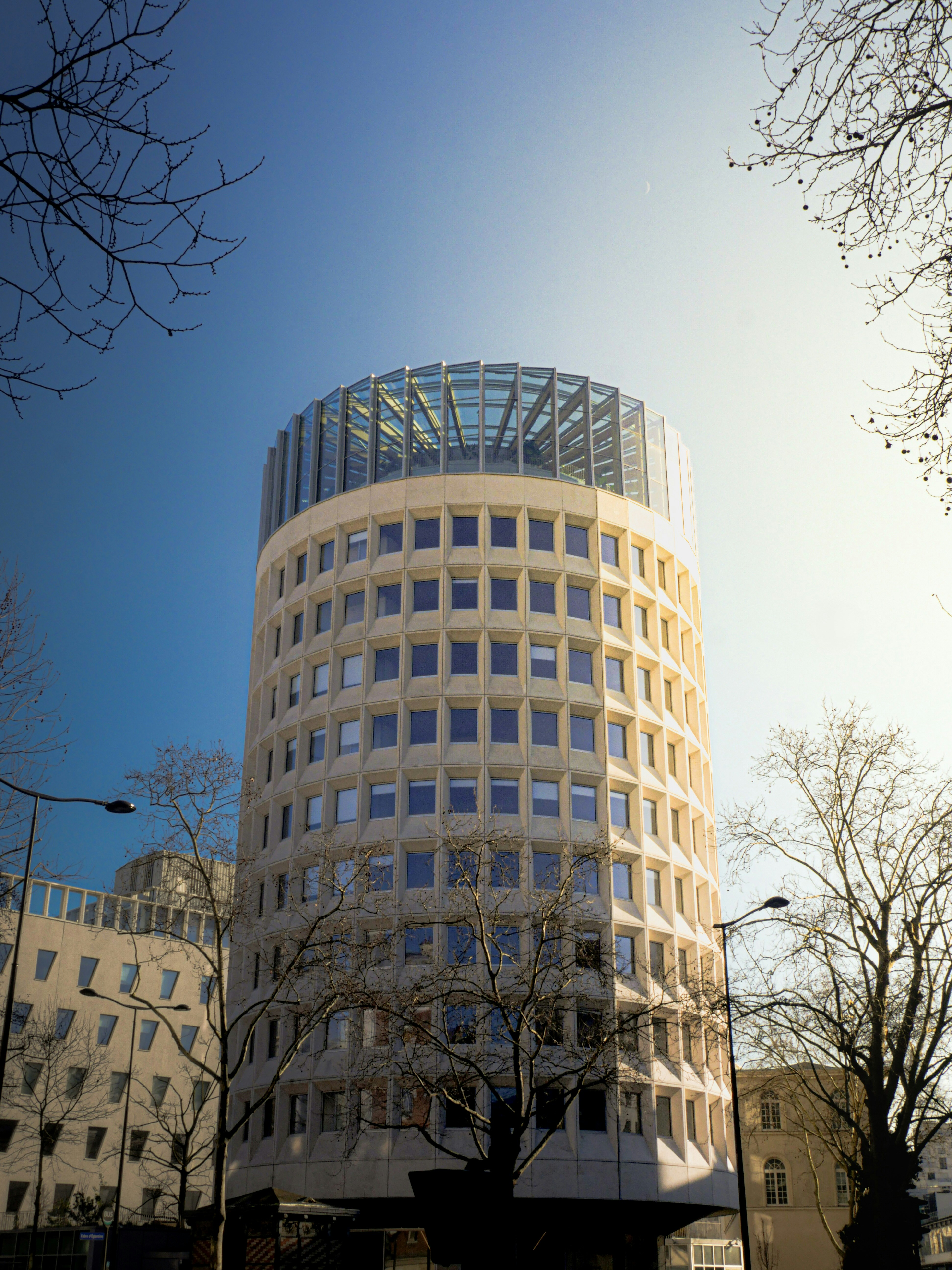 Circular tower rising above a sunlit urban street
