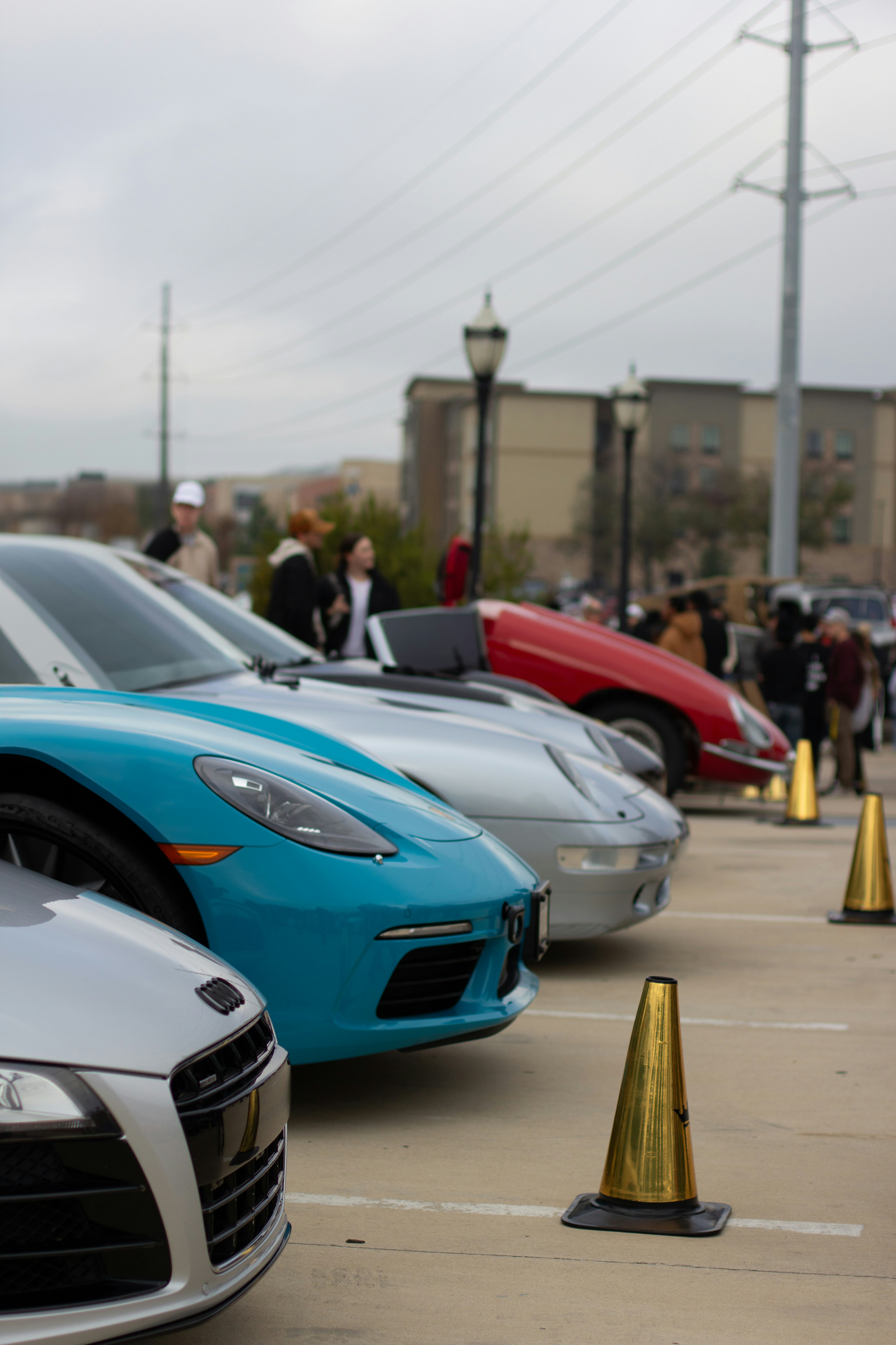 Row of polished sports cars huddle in a sunlit parking lot.