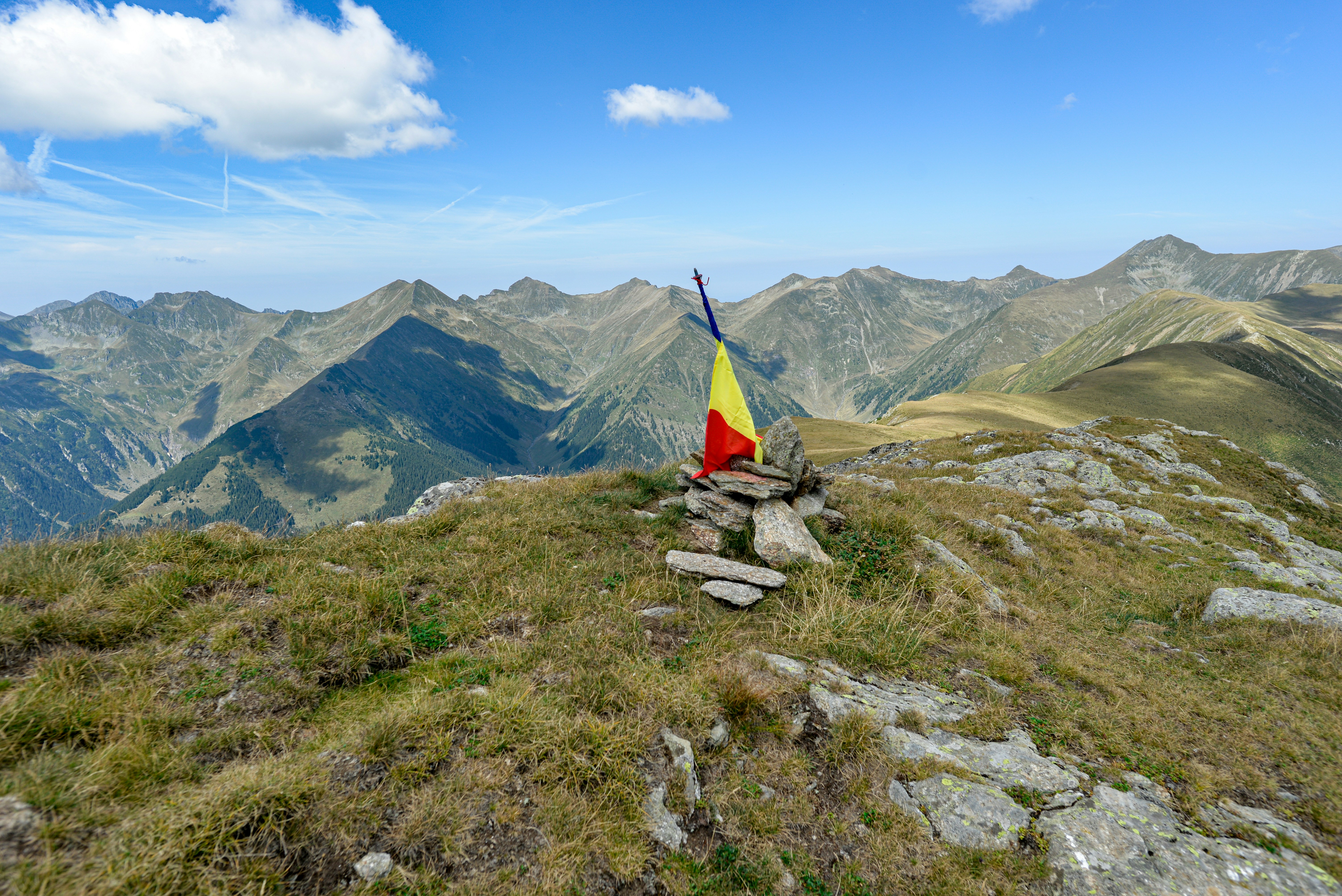 Flag on a Rocky Crest Overlooking Alpine Valleys
