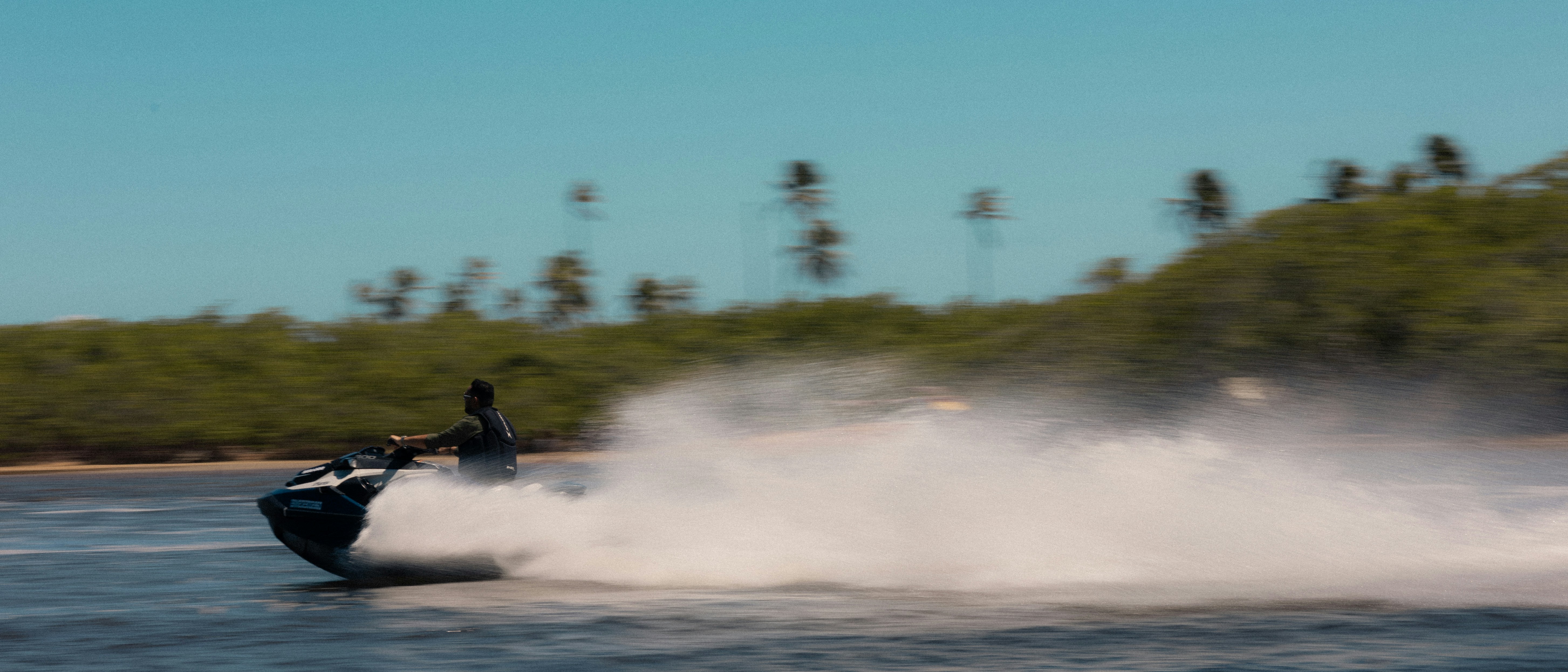 Wake Runner: Jet Ski Slice Through Spray Along a Palm-Fringed Shore