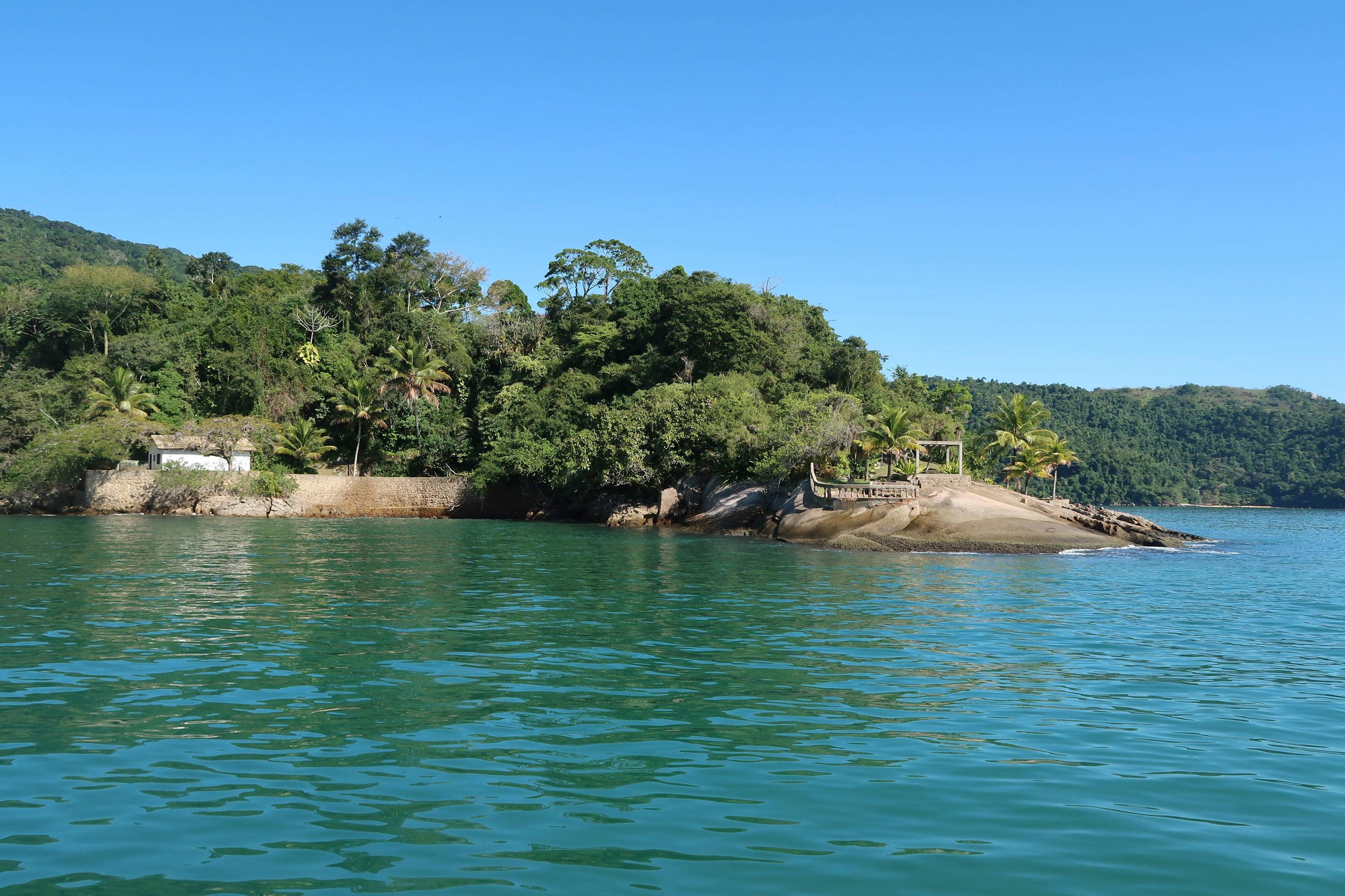 Mar calmo em ilha no Rio de Janeiro | A body of water with a small island in the middle of it
